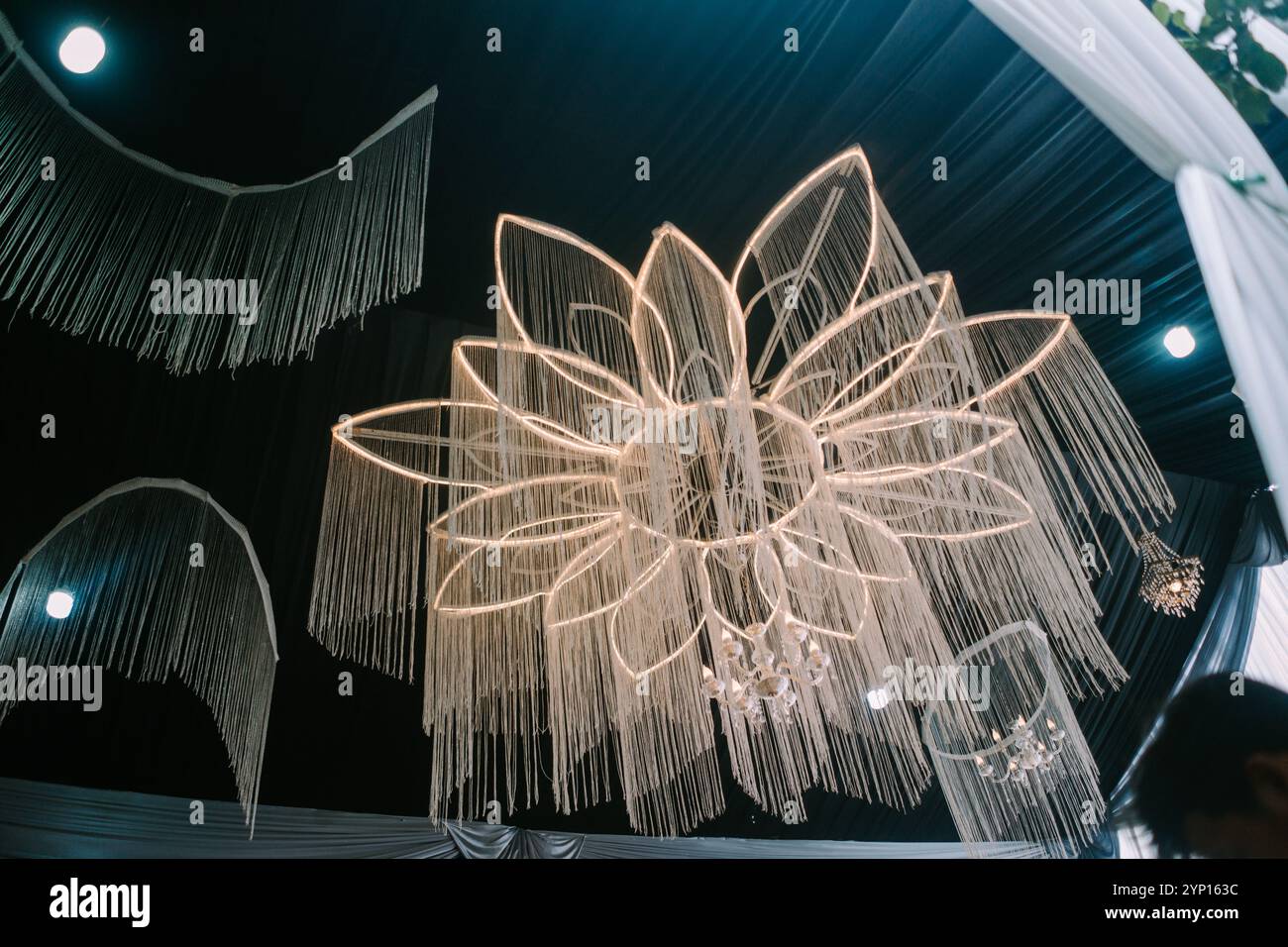 An elegant floral-shaped chandelier with glowing string lights and ...