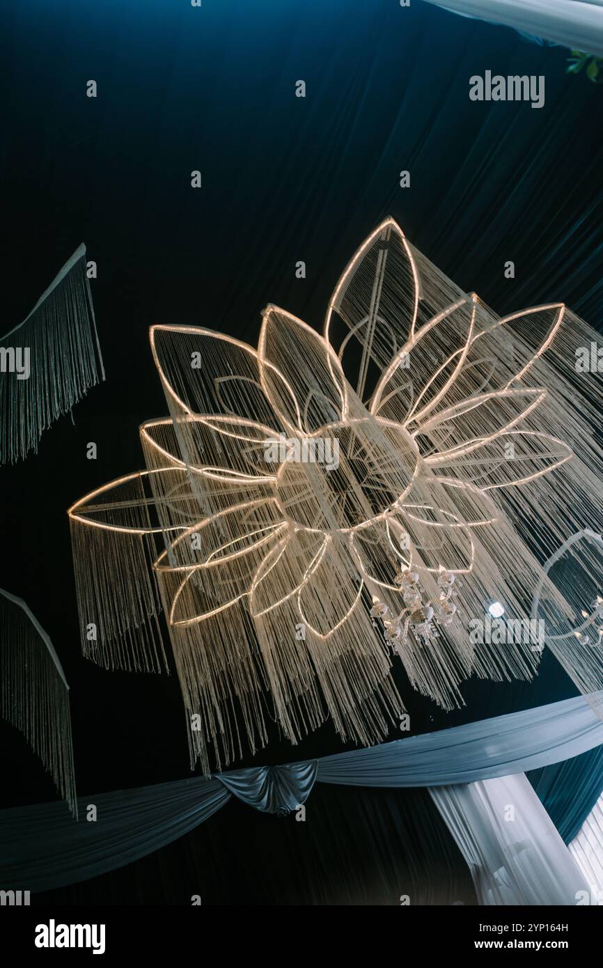 An elegant floral-shaped chandelier with glowing string lights and ...