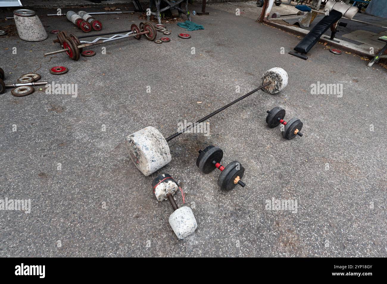 Old homemade barbell and dumbbells made of concrete bucket on the ...