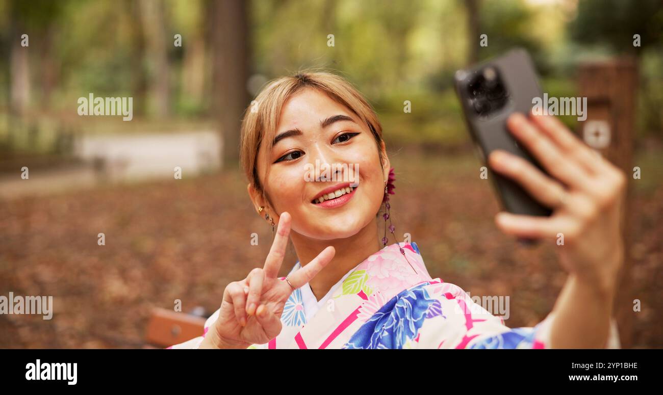 Selfie, park and woman in nature, peace sign and happy for memory on vacation, travel and kimono ...