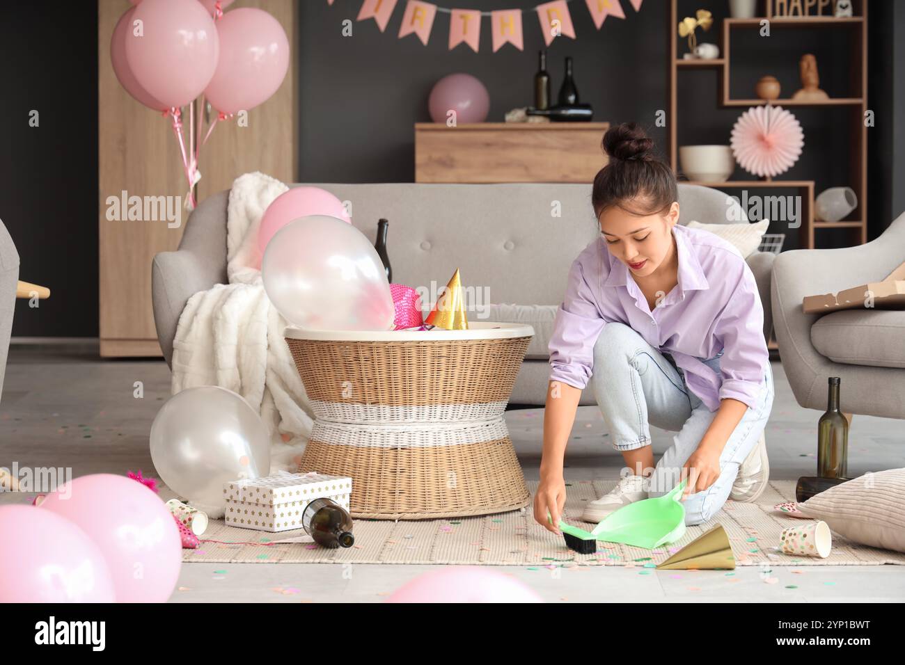 Young Asian woman sweeping confetti from carpet in messy room after ...