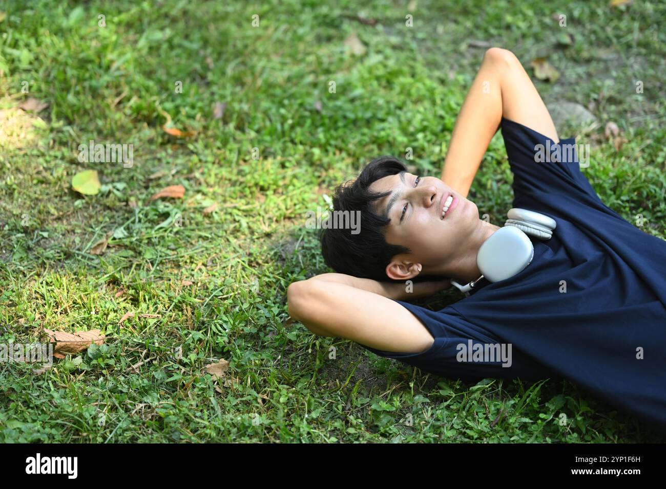 Young man relaxing after a jog lying down on the grass in park with ...