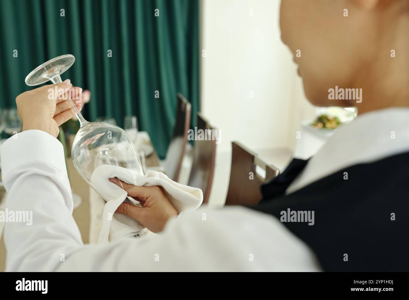 Restaurant staff carefully polishing wine glass before dinner service ...