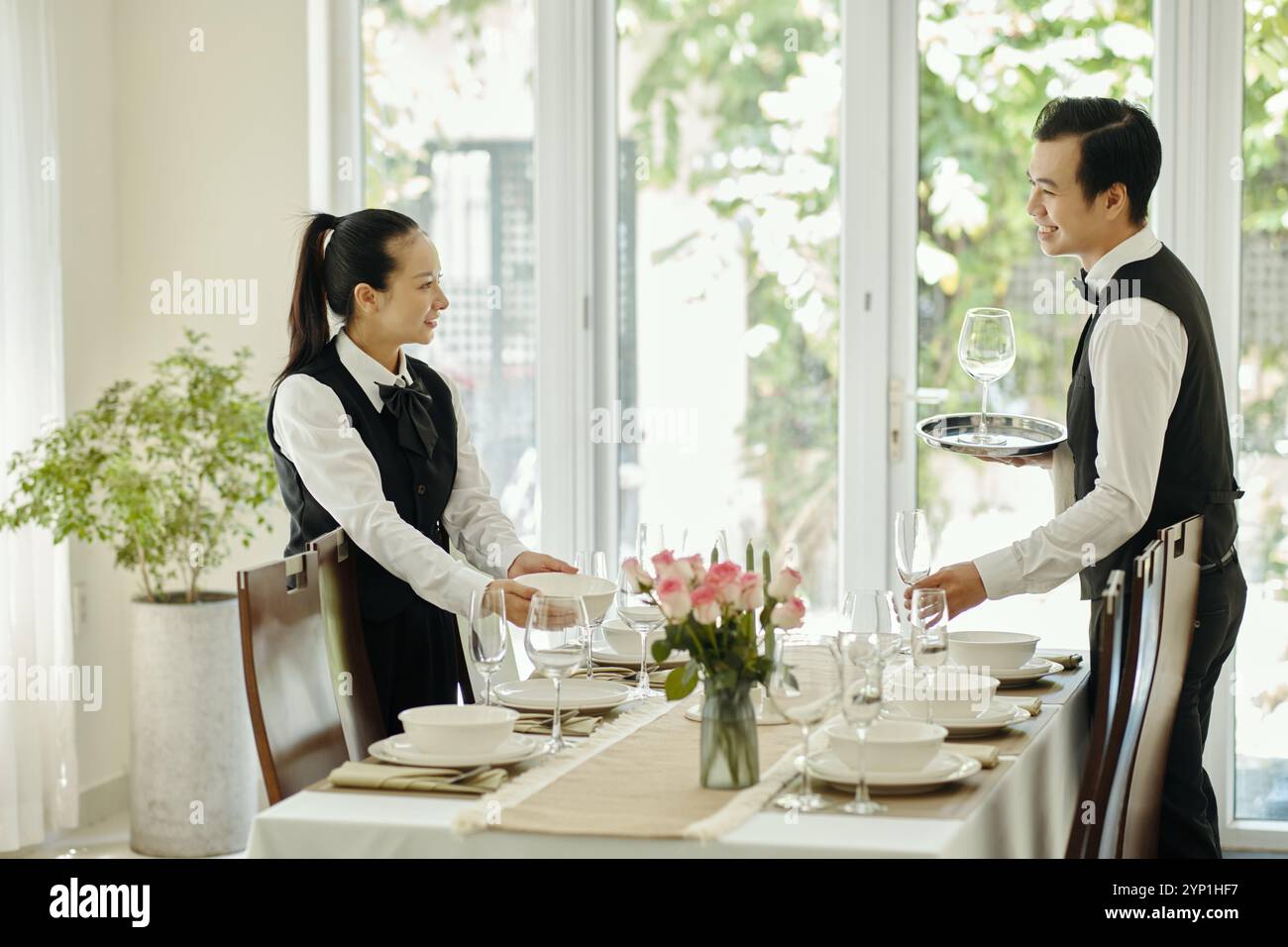 Setting Up Table in Elegant Restaurant with Waitstaff Coordinating ...