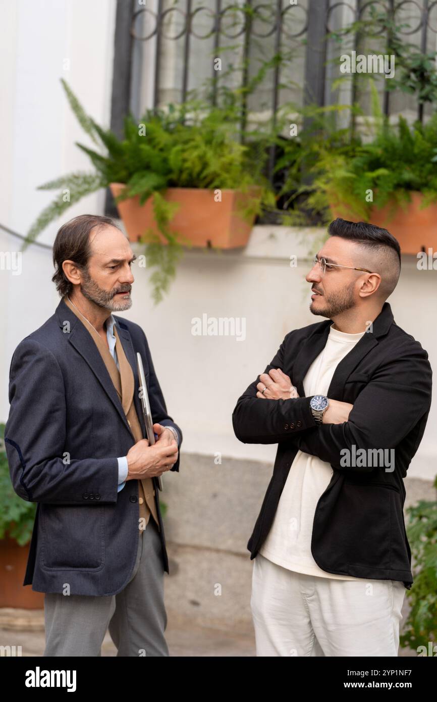 Two businessmen are having a conversation outside their office building ...