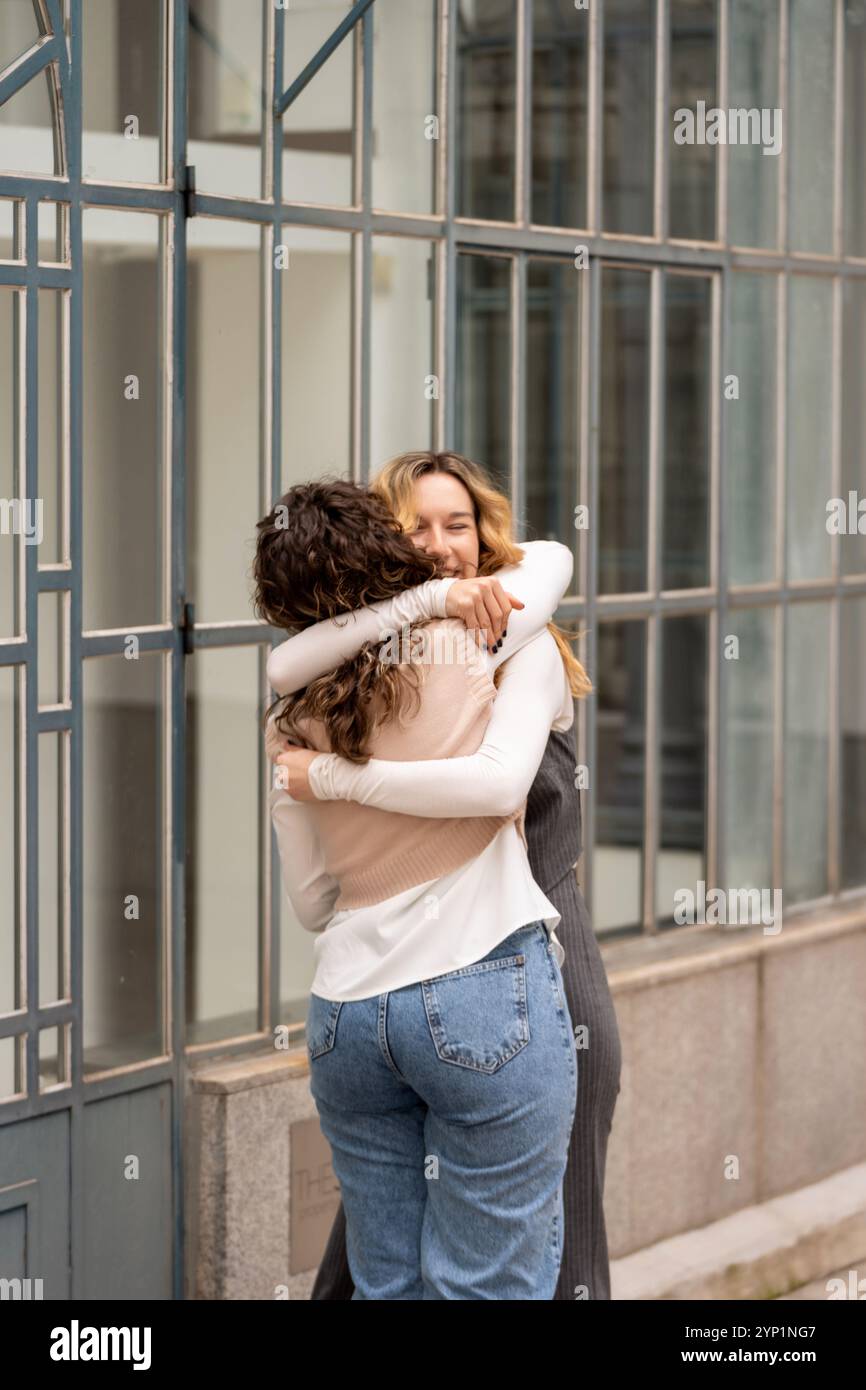 Two young women are embracing each other tightly, expressing joy and ...