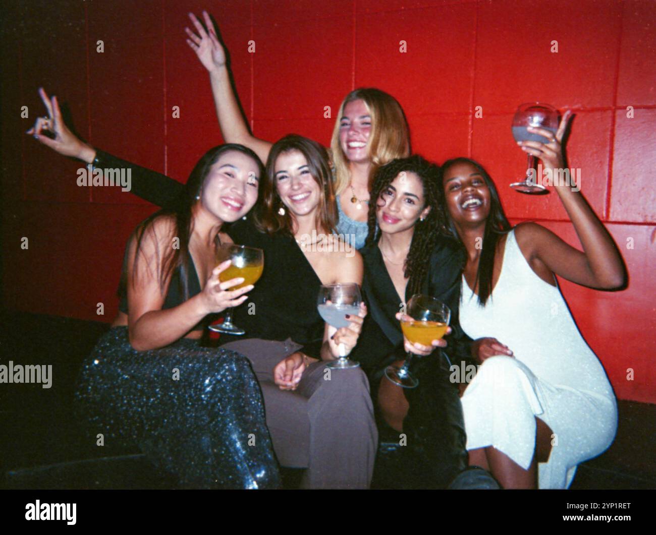 A group of friends enjoy a fun night out, holding drinks and ...