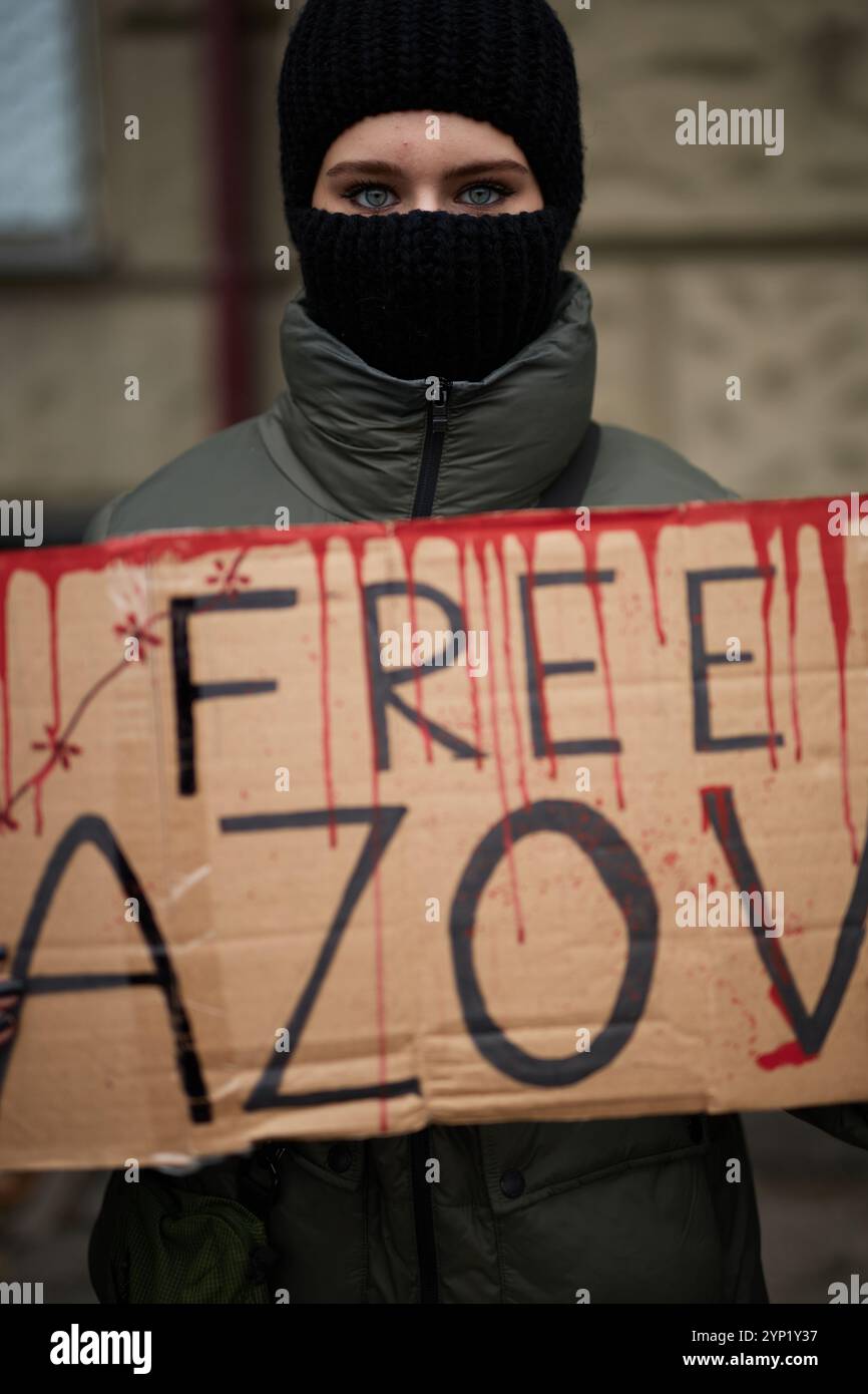 Young Ukrainian girl in balaclava posing with a poster Free Azov. Kyiv ...