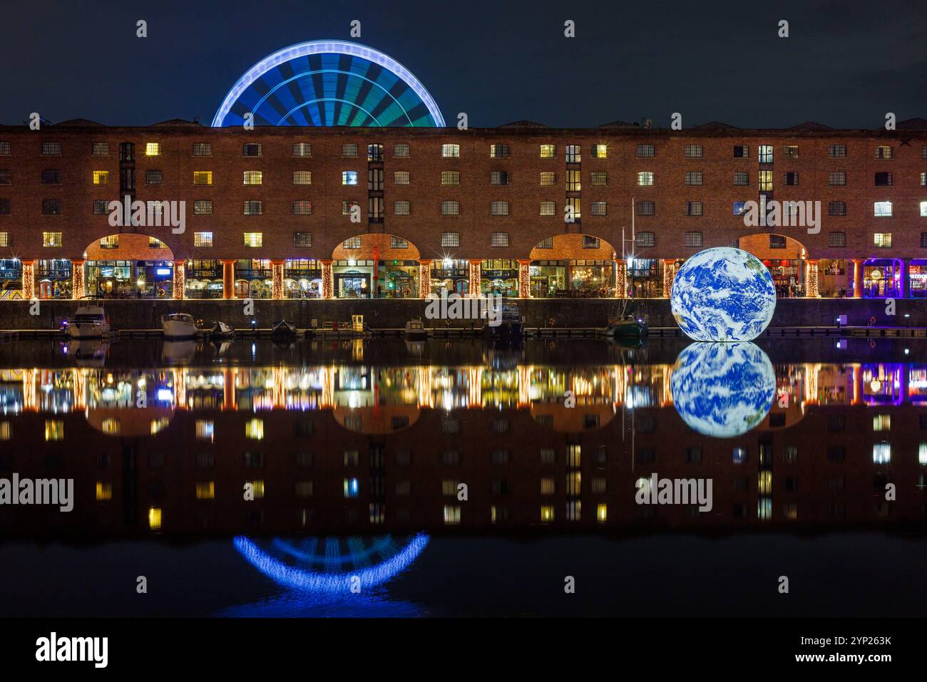 A stunning illuminated Earth installation reflecting on the water at ...