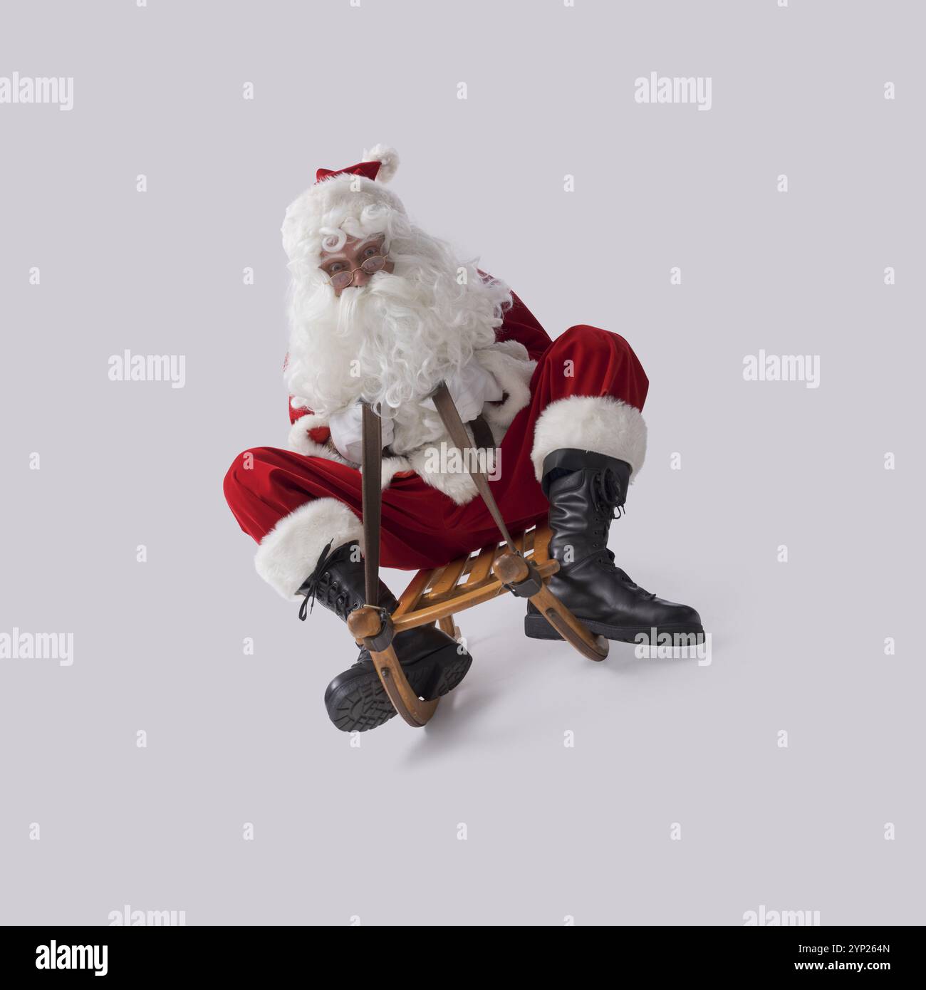 Funny excited Santa Claus riding a fast small wooden sleigh, Christmas ...