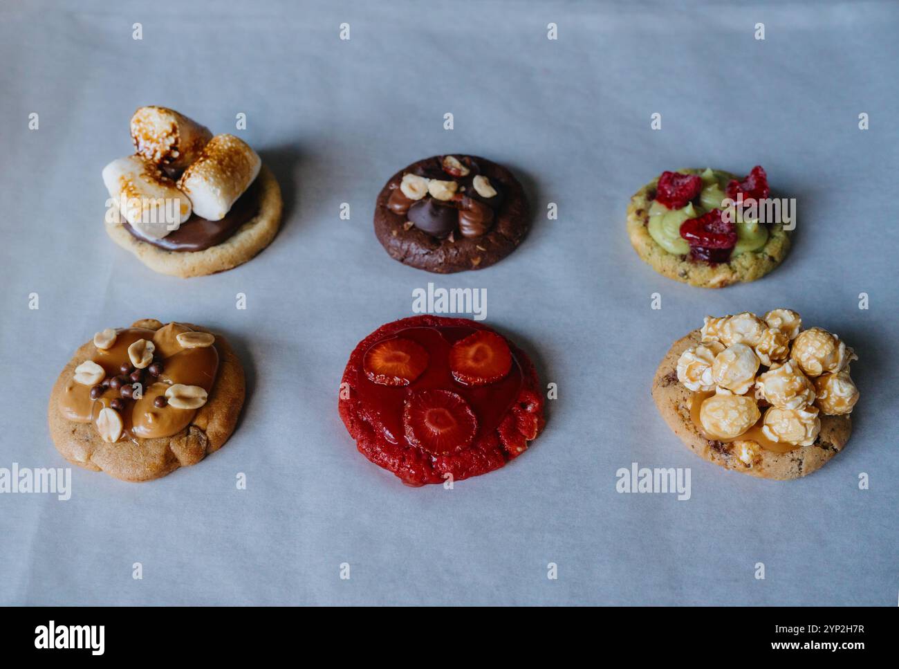 Homemade round cookies on baking paper with different toppings ...