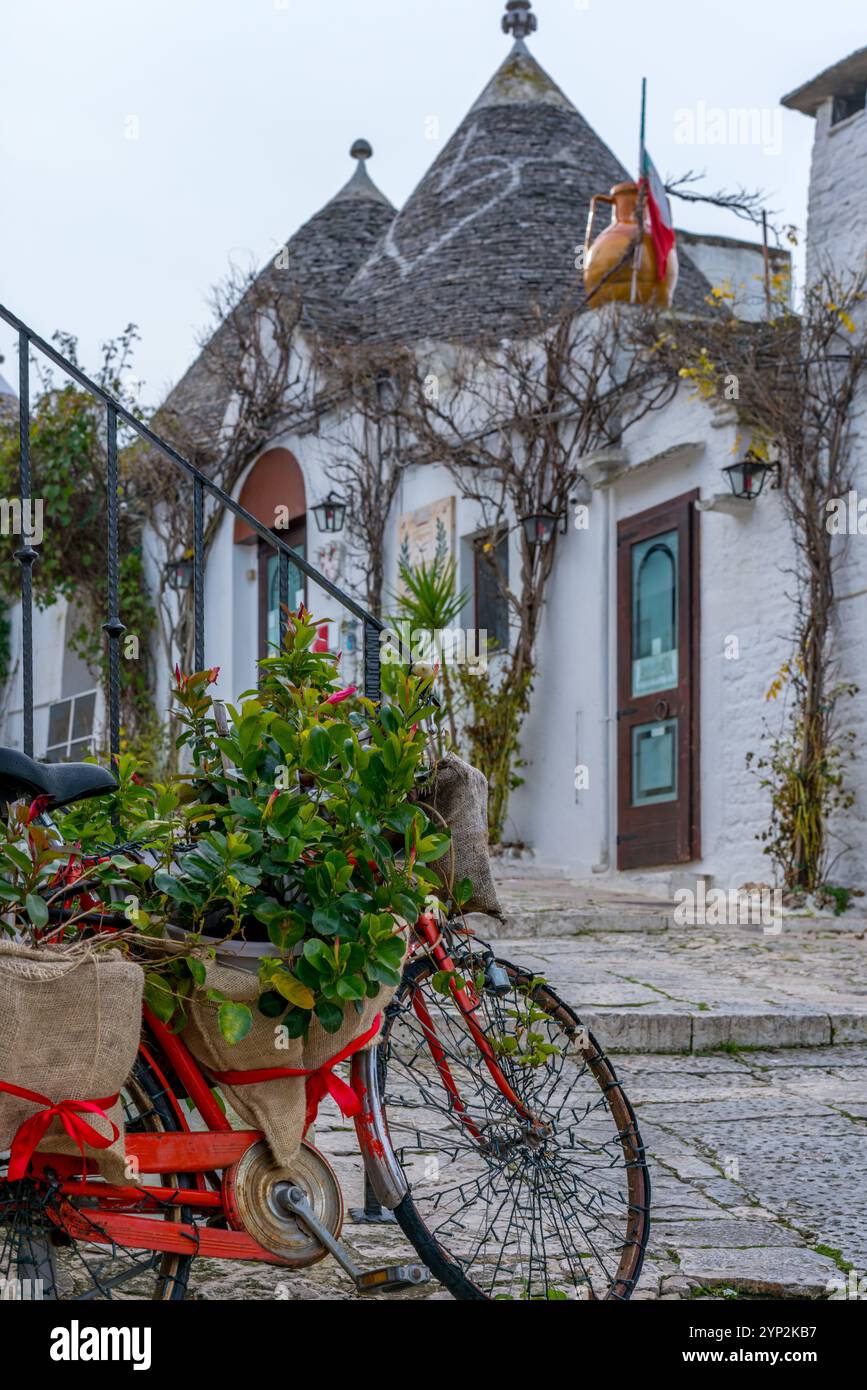 Red bike with flowers near an iconic Trullo house with conic ceiling in ...