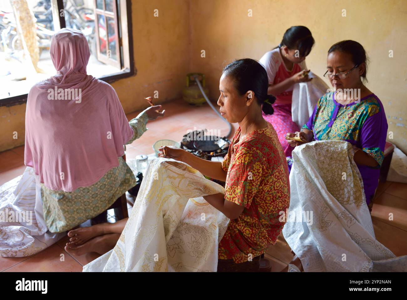 Women using a pen-like tool (canting) to apply liquid hot wax in the ...