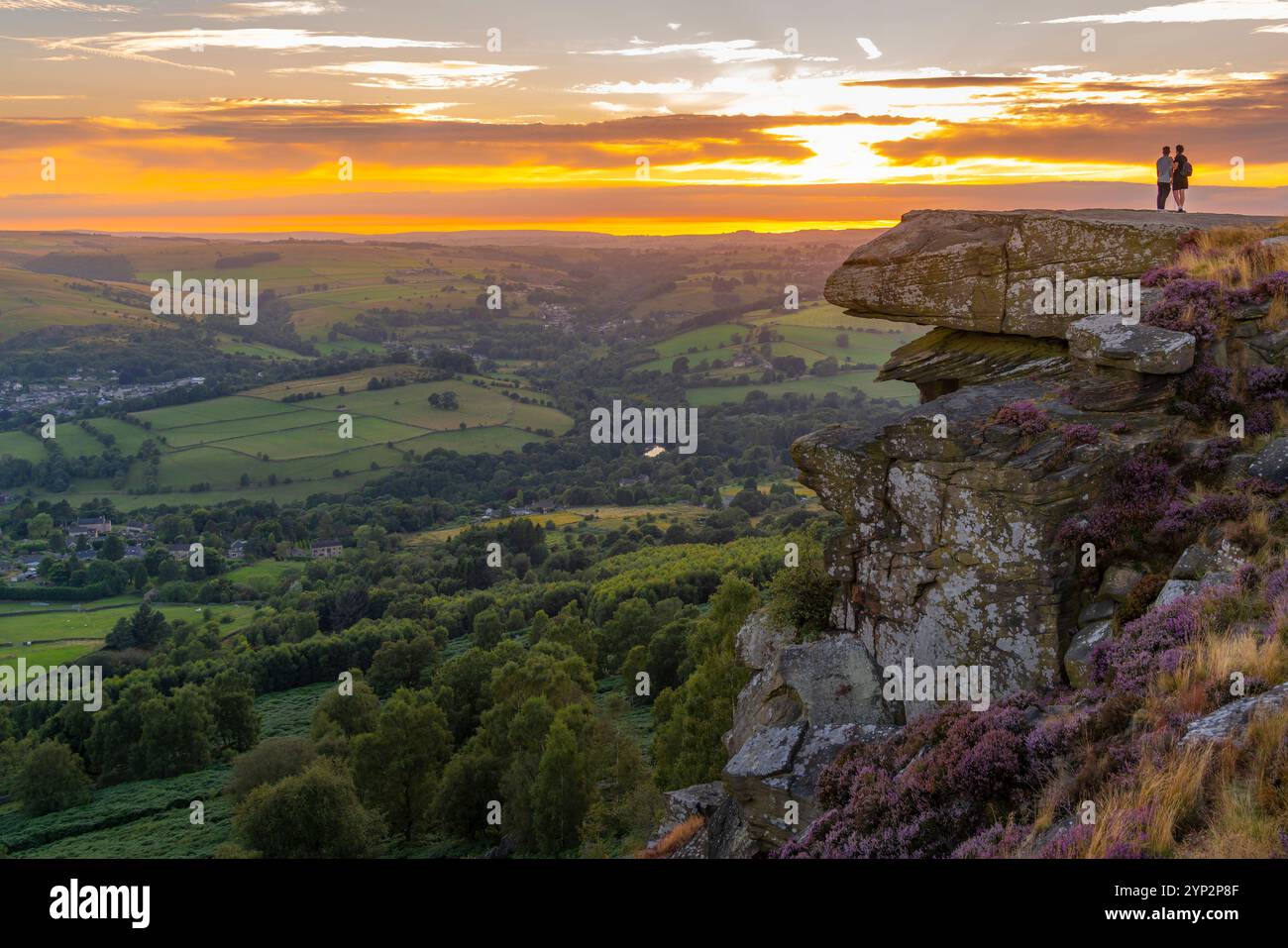 View of man and woman viewing landscape from Curbar Edge at sunset ...