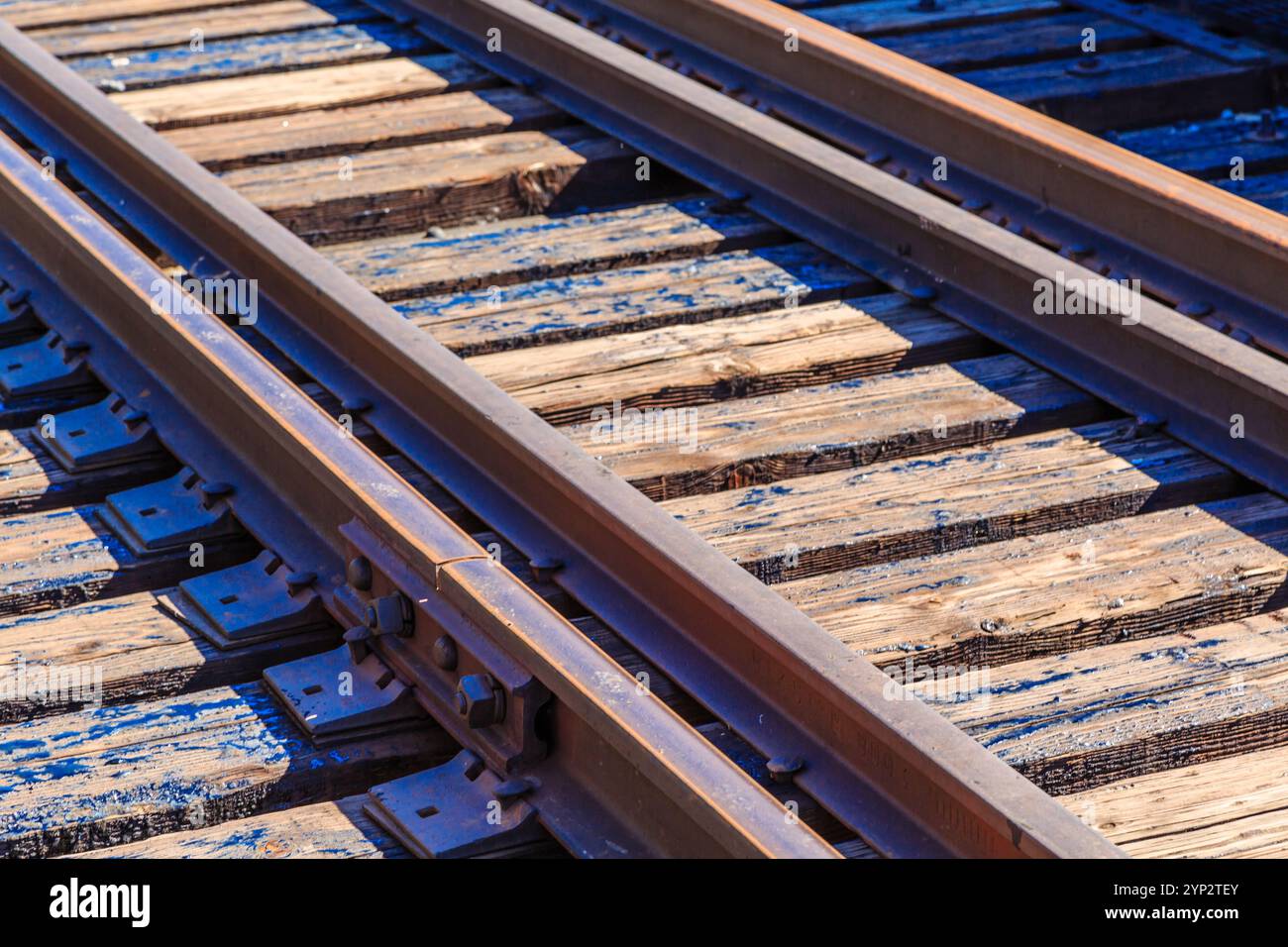 The train tracks are made of wood and metal. The tracks are blue and ...