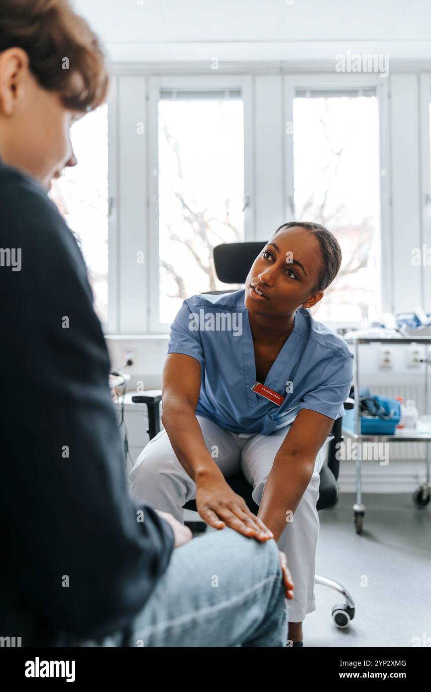 Female healthcare worker checking leg of patient while sitting in ...