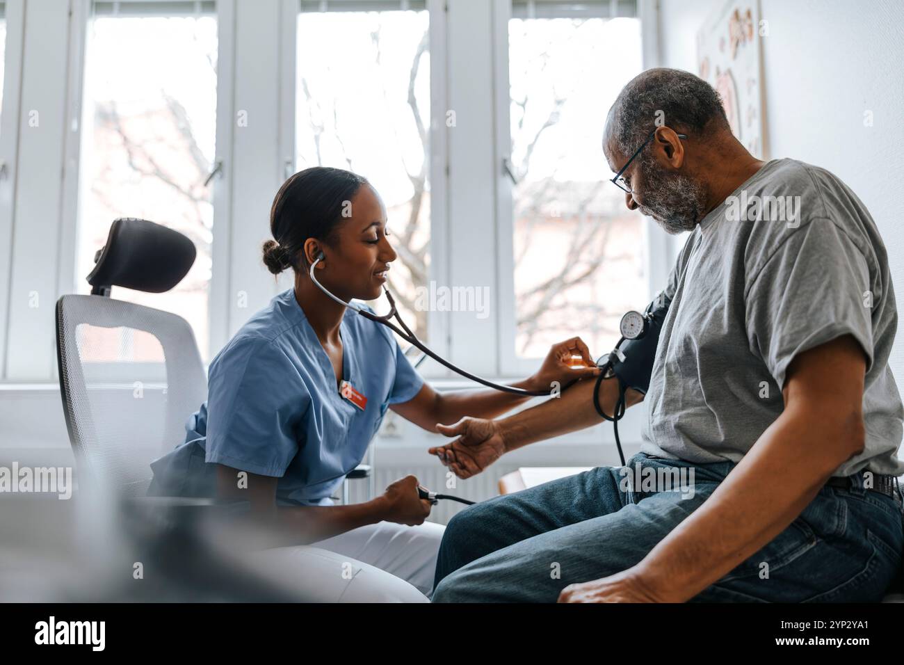 Side view of female doctor checking senior patient's blood pressure ...