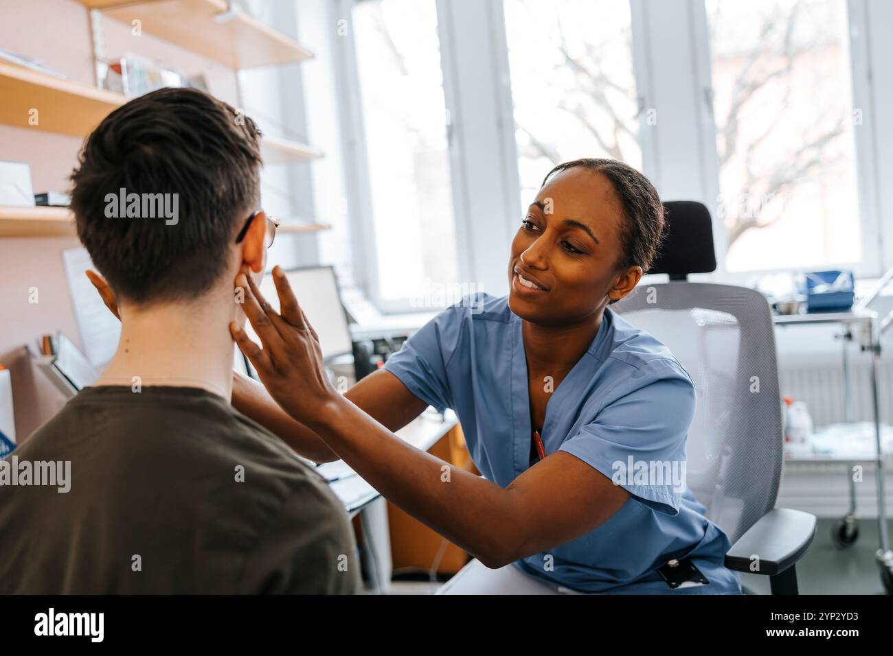 Smiling female medical professional checking lymph nodes of patient in ...