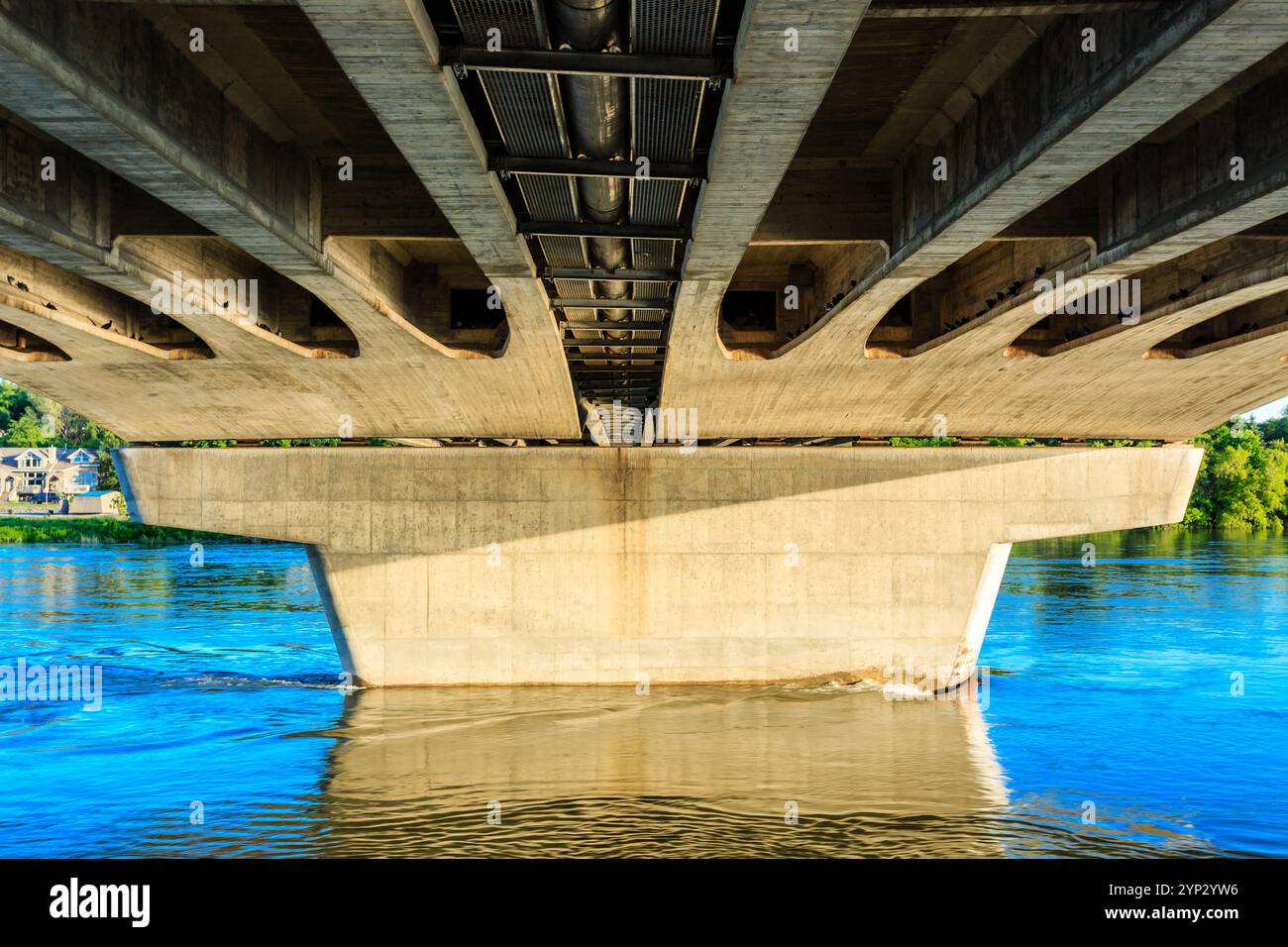 A bridge is shown from the underside, with the water below and the sky ...