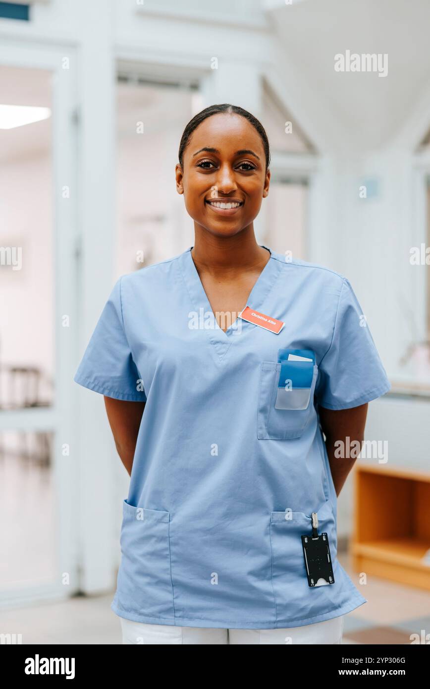 Portrait of smiling female medical expert wearing blue scrub while ...