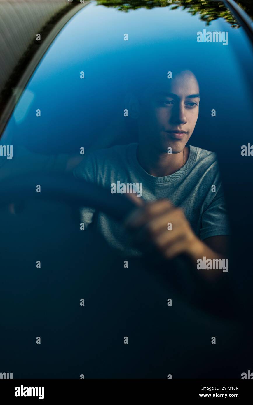 Thoughtful young man sitting in car seen through windshield Stock Photo ...