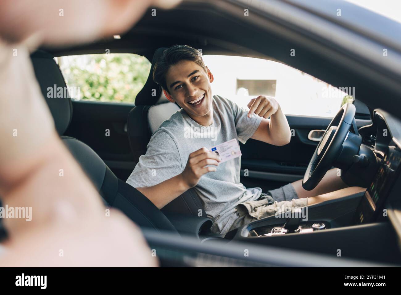 Happy young man showing drivers license while sitting in car Stock ...