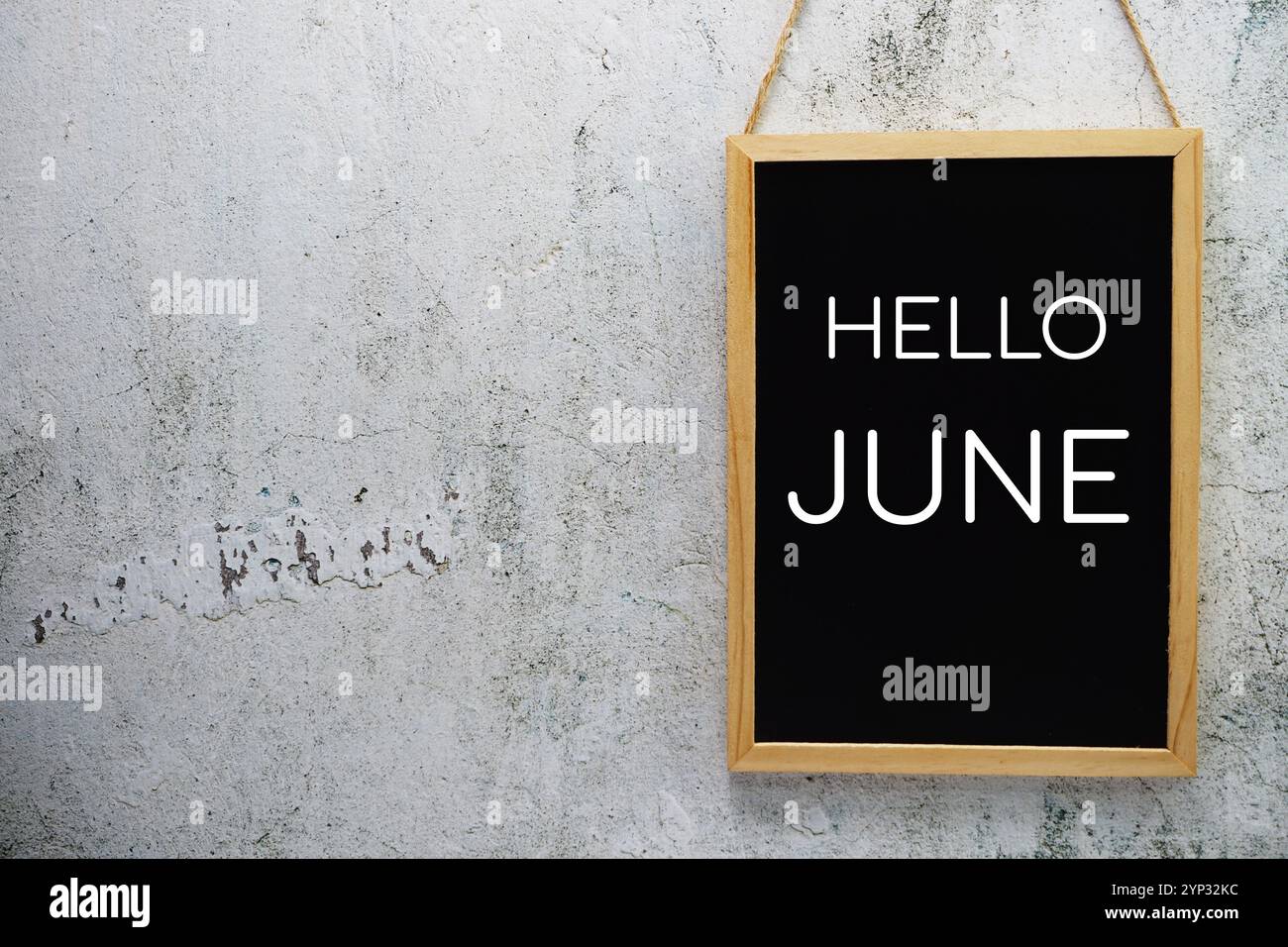 Hello June typography text on blackboard hanging against on the wall ...
