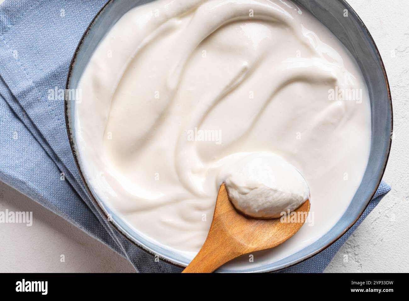 Homemade Greek Yogurt or Labne in blue bowl with wooden spoon close up ...