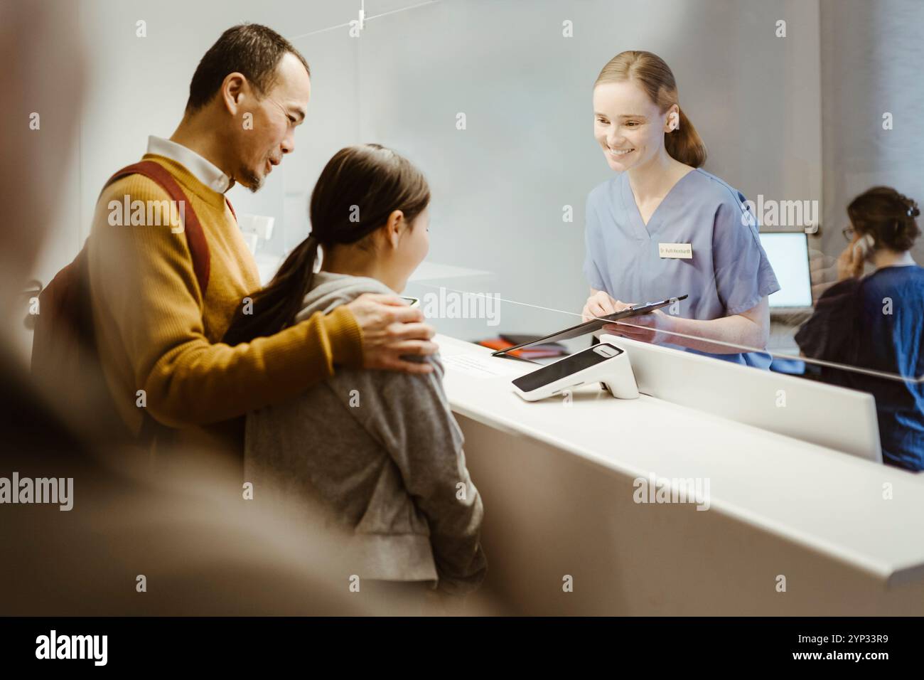 Smiling female receptionist booking appointment for girl at reception ...