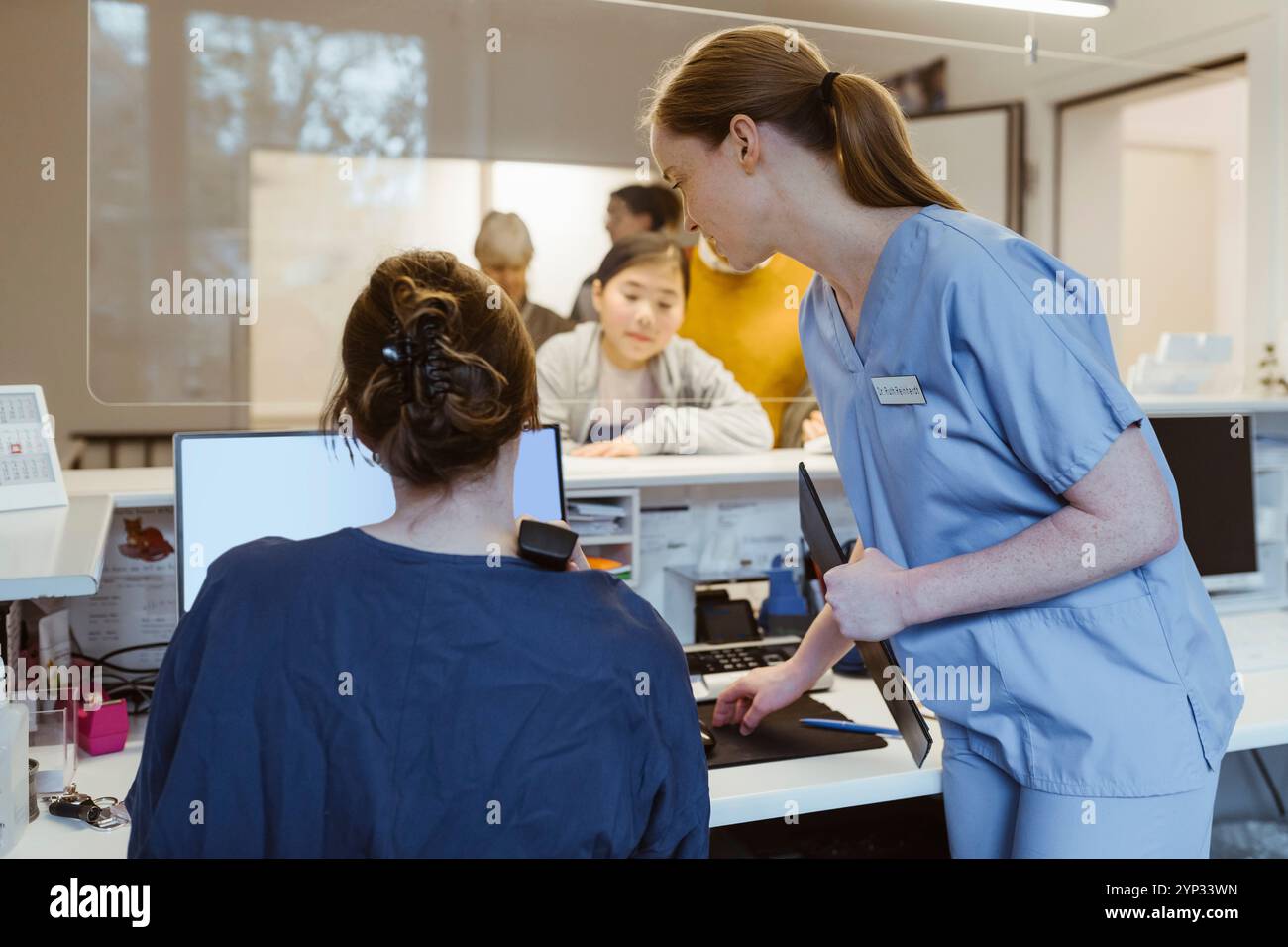 Female medical team helping each other while working hospital reception ...