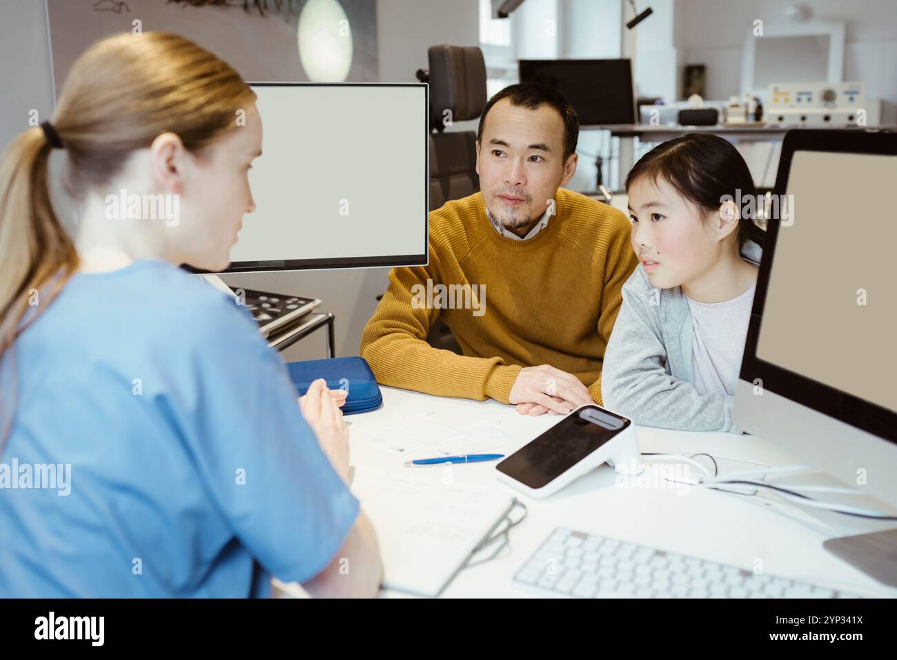 Female pediatrician advising girl sitting with father in clinic at ...