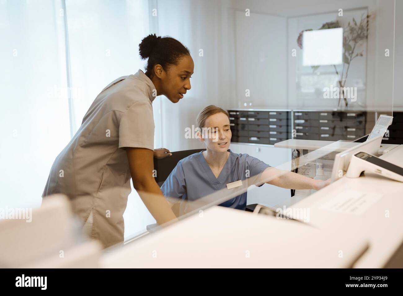 Female healthcare experts discussing over computer while working at ...