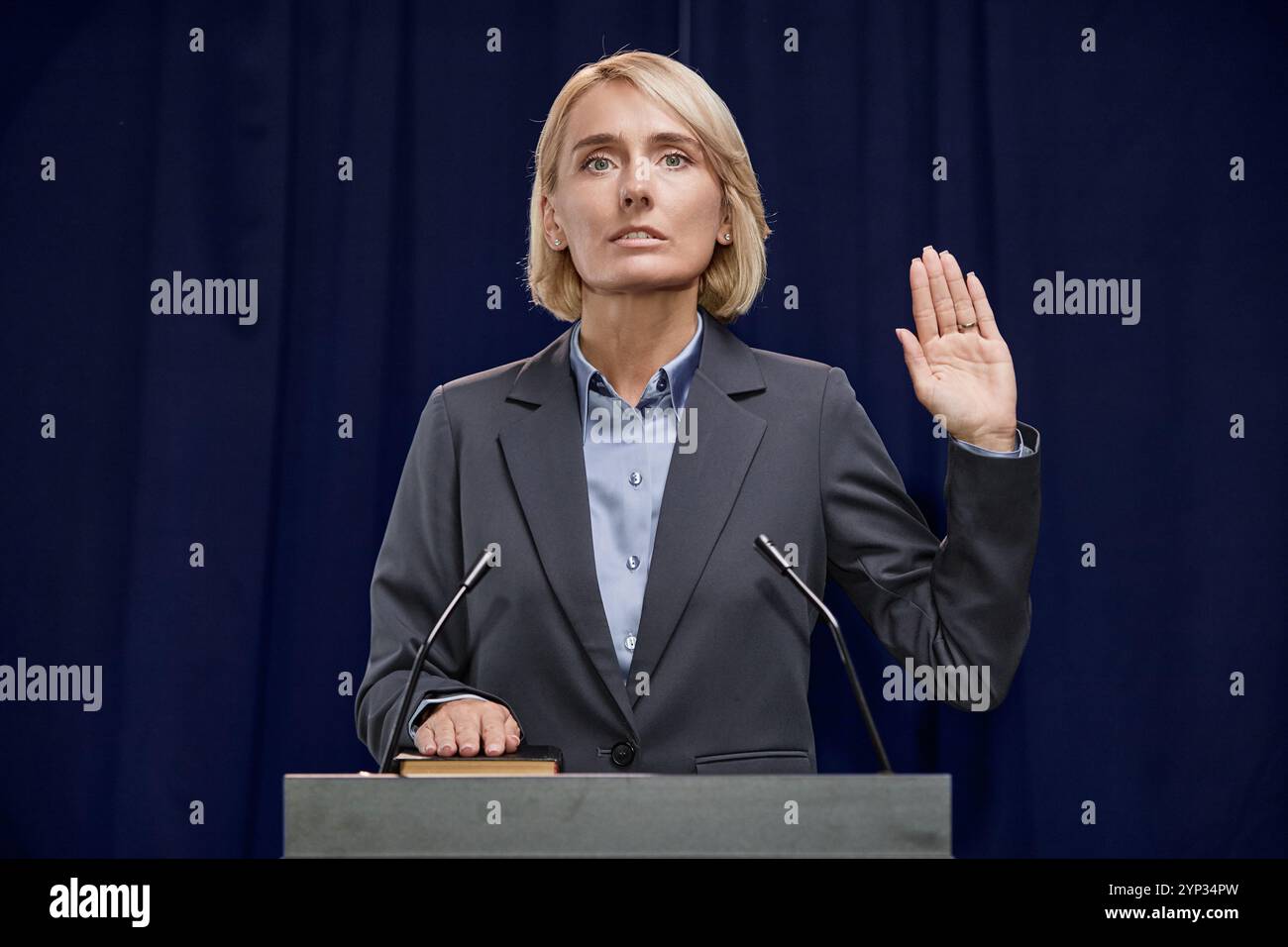 Portrait of female politician in formal attire with one hand on book ...