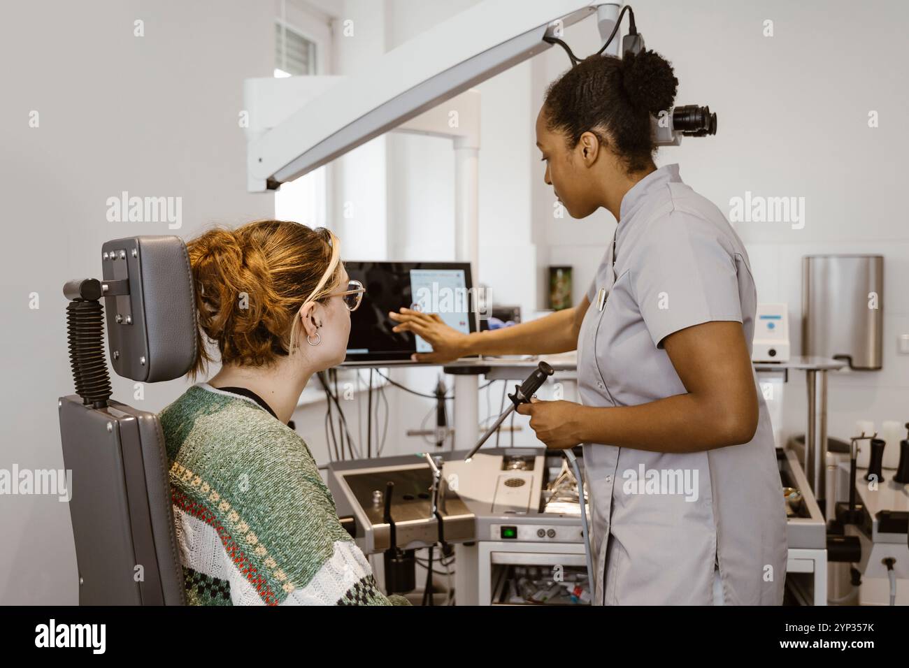 Side view of female Ophthalmologist programming machine during eye test ...