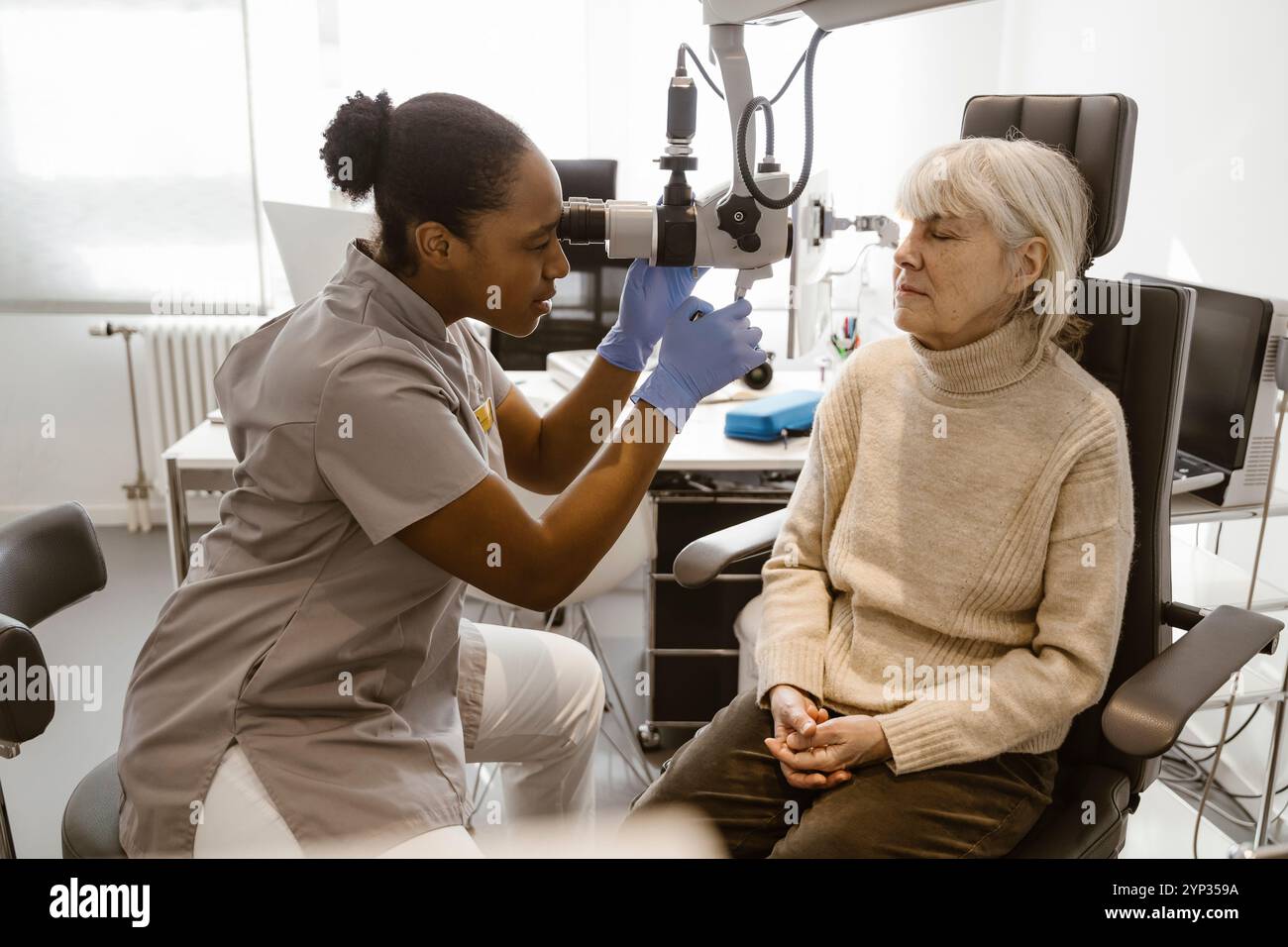 Side view of female eye specialist scanning eye of senior woman at ...