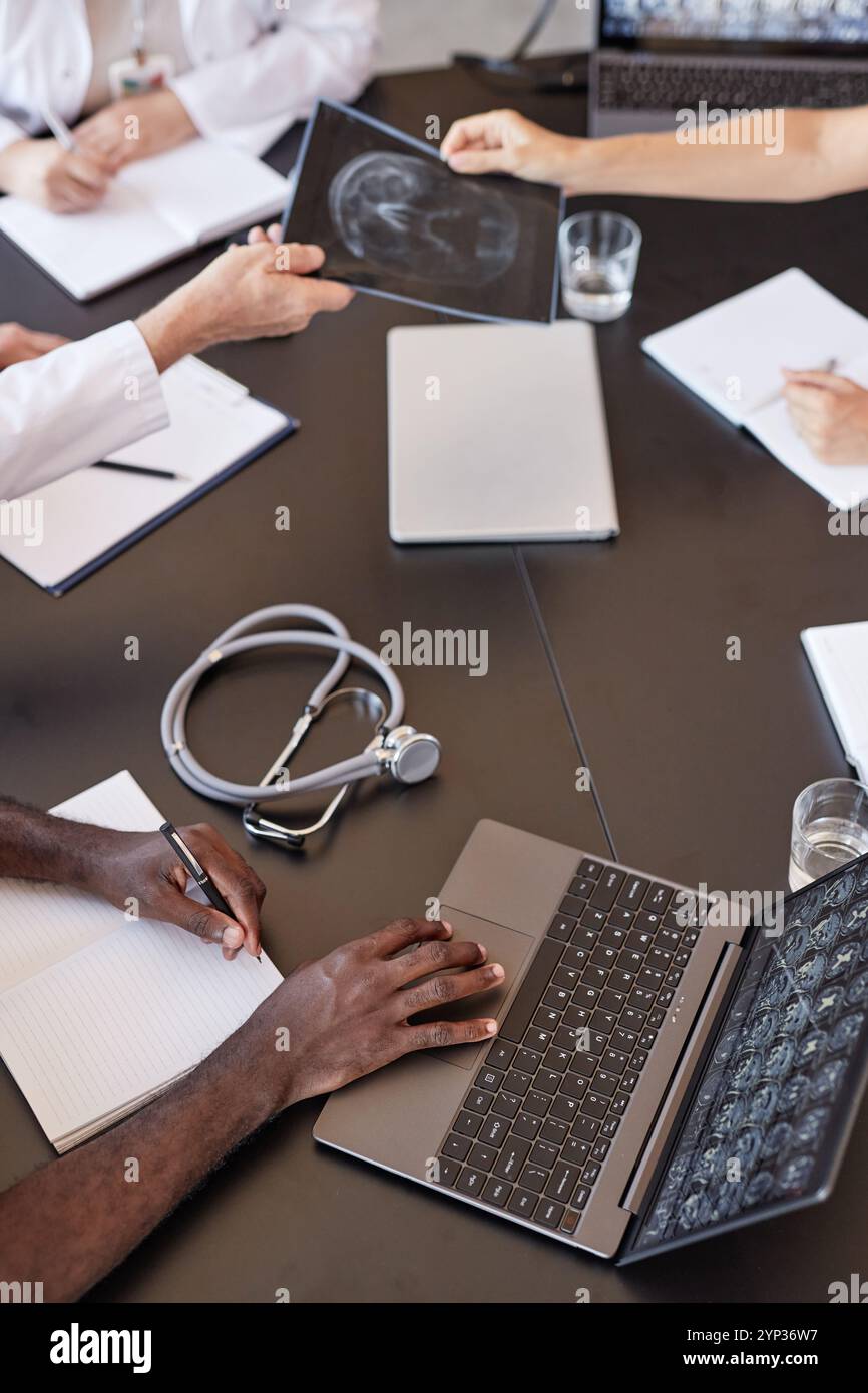 Vertical shot of Black man writing notes on paper keeping fingers on ...