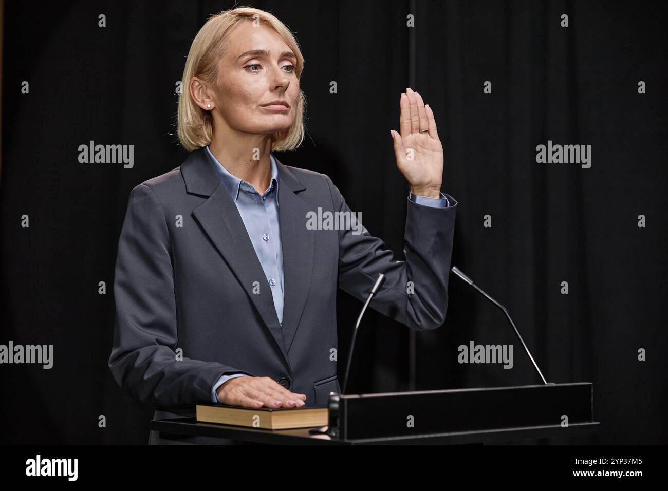 Medium shot of female politician in formal attire with one hand on book ...