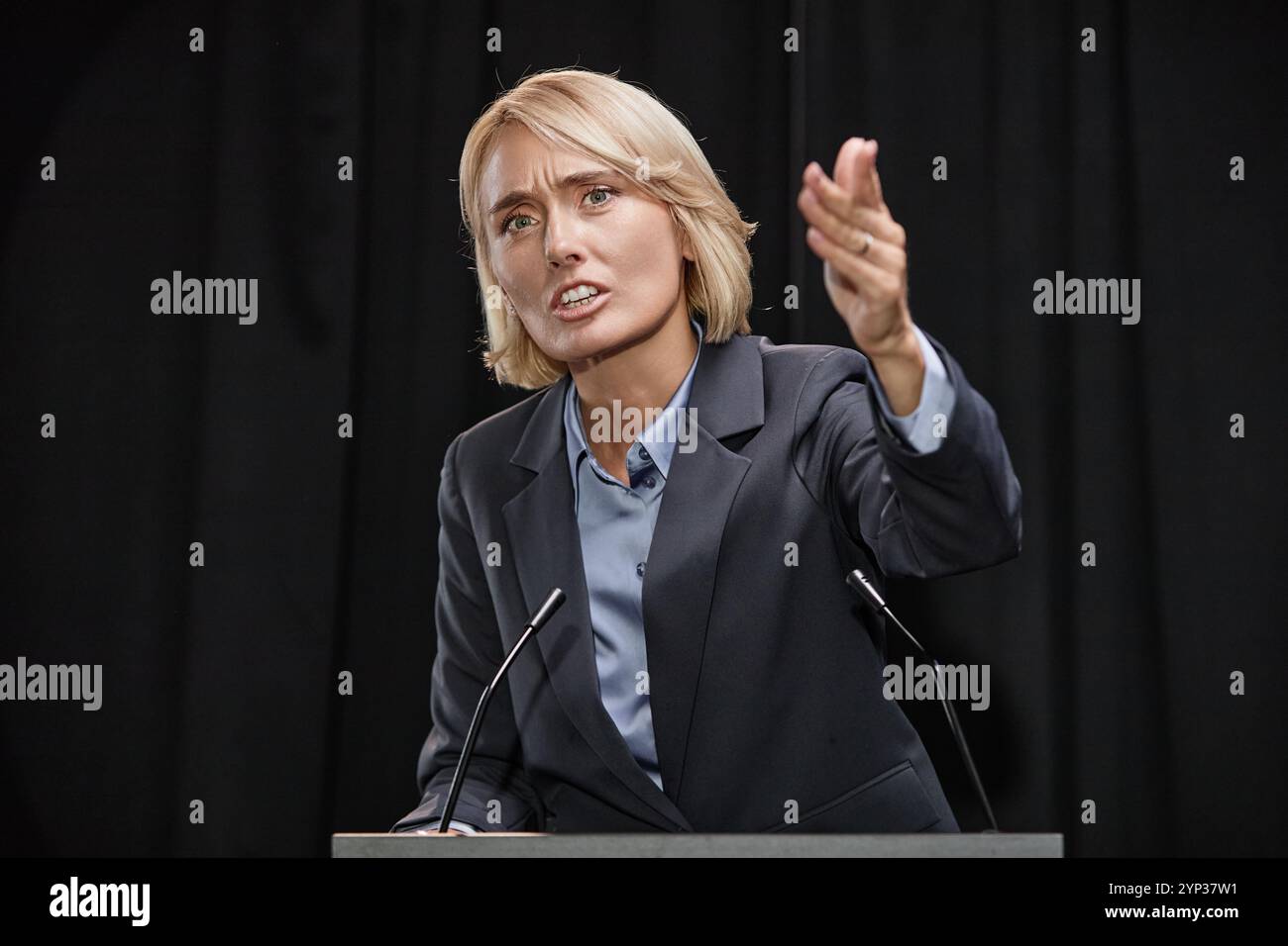 Medium shot of emotional female politician in blue suit gesticulating ...