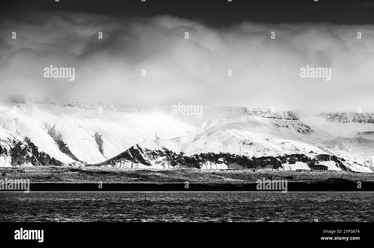 Coastal Icelandic landscape with snowy mountains under dark dramatic ...