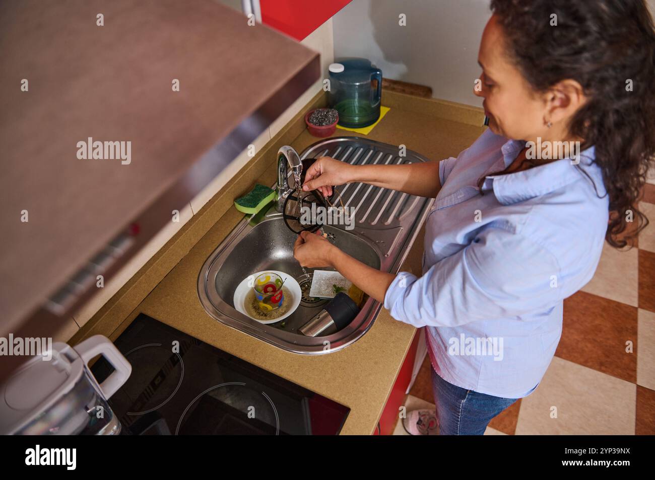 A woman washing dishes in a modern kitchen, focusing on cleaning with ...