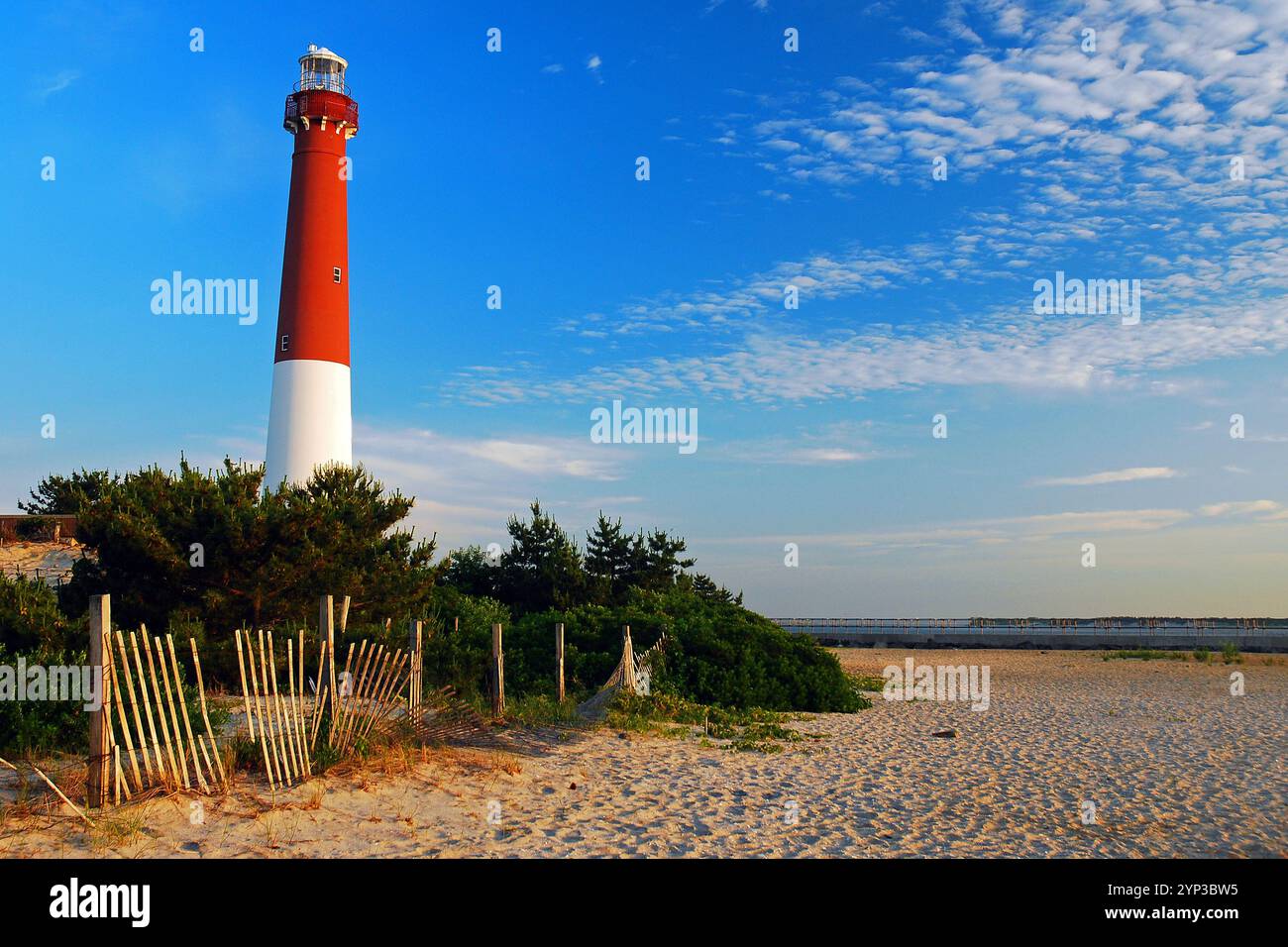 The red and white Barnegat Lighthouse stands above the sand dunes on ...