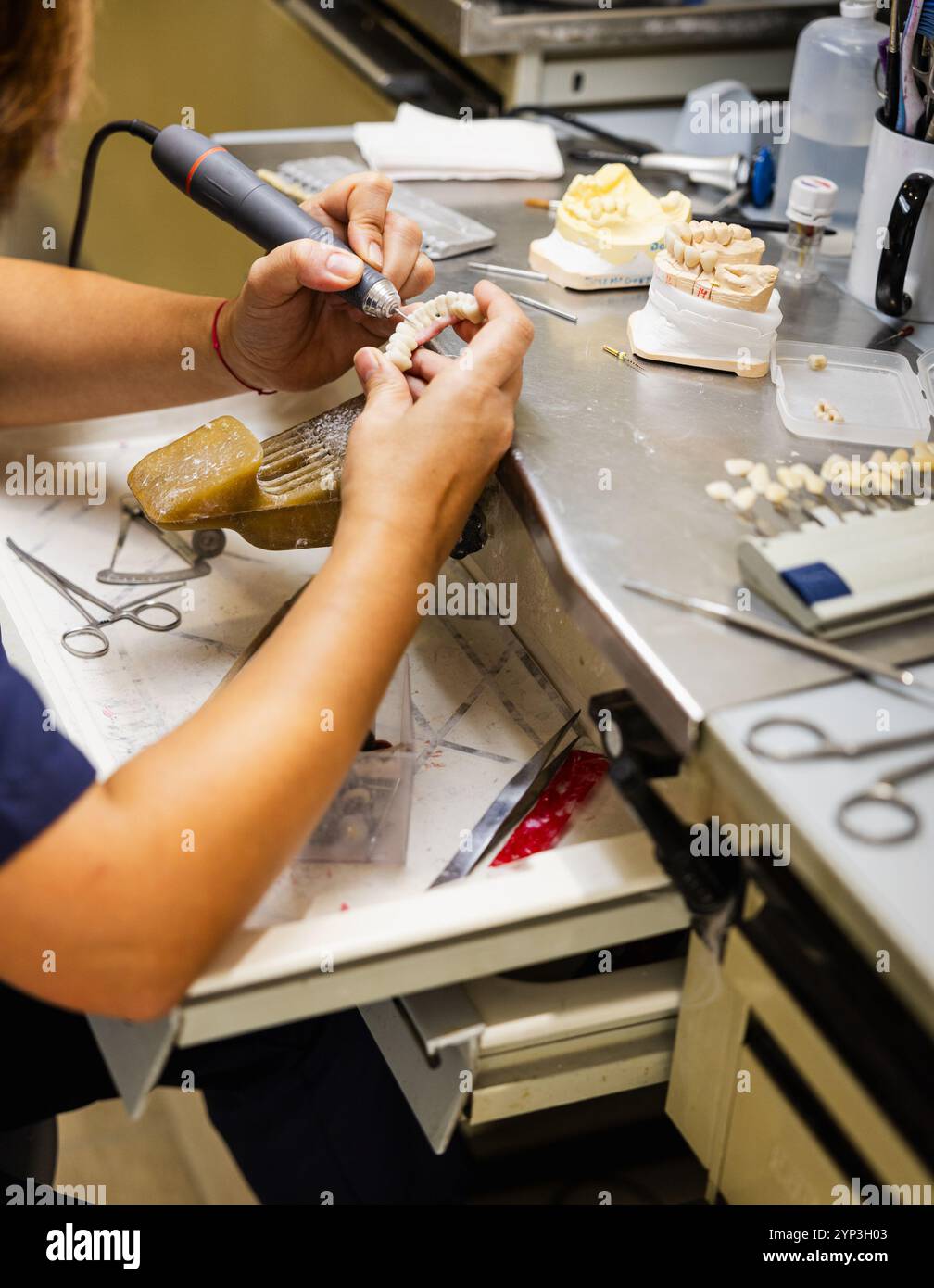 A dental technician working meticulously on prosthetic teeth in a well ...