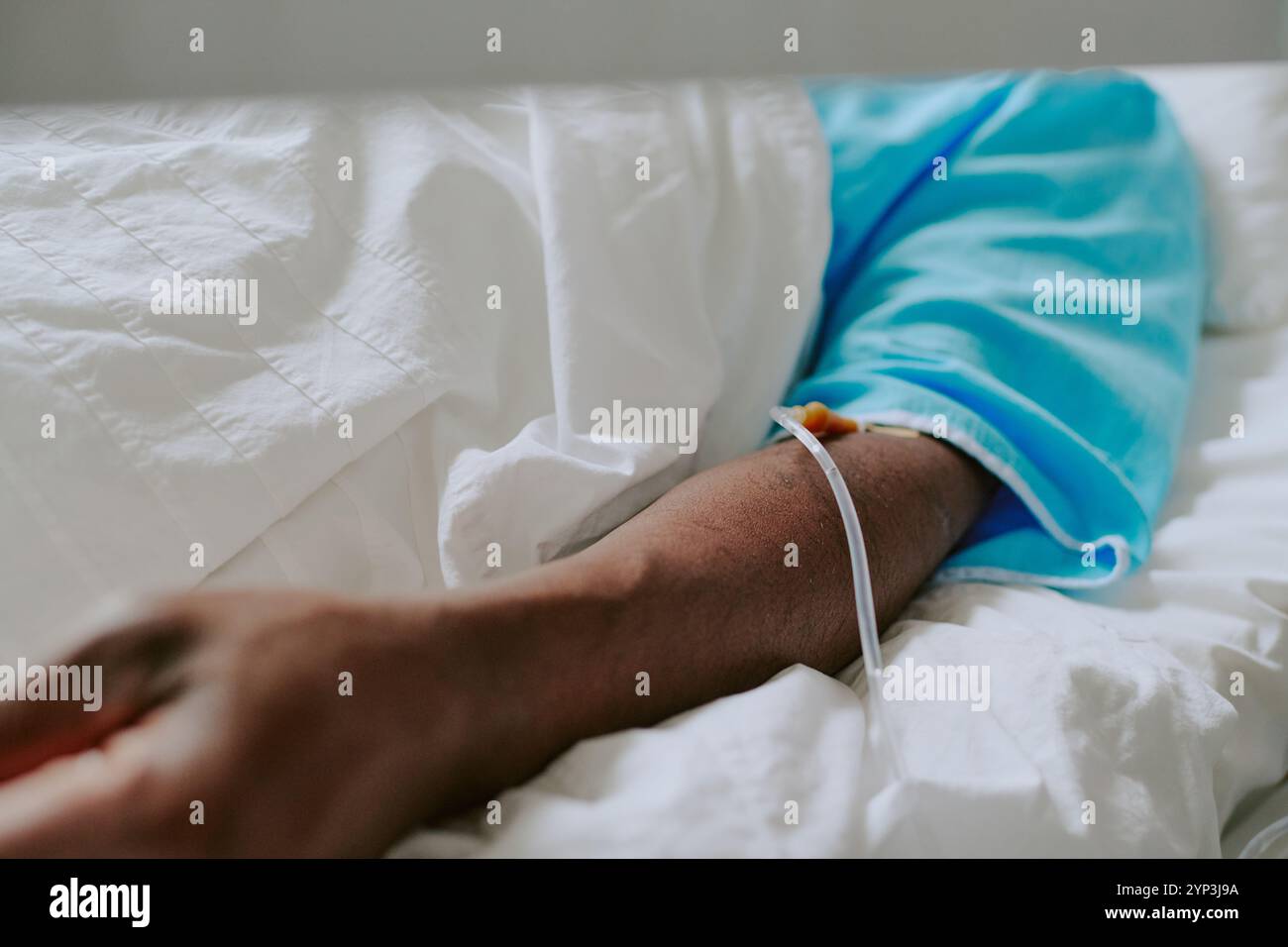 Patient lying in hospital bed with IV drip connected into arm ...