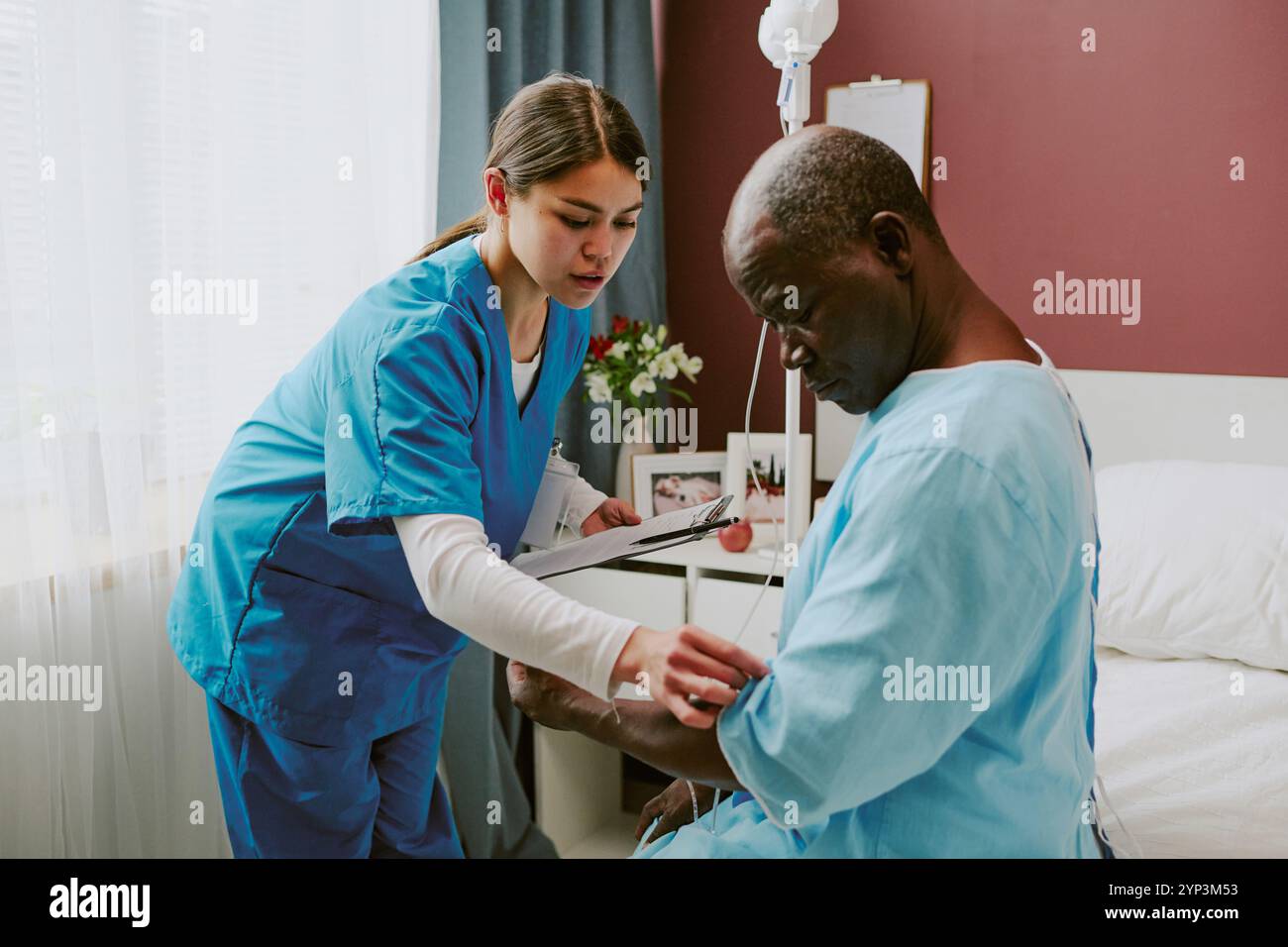 Nurse providing medical care to senior black patient sitting in hospital room with healing ...