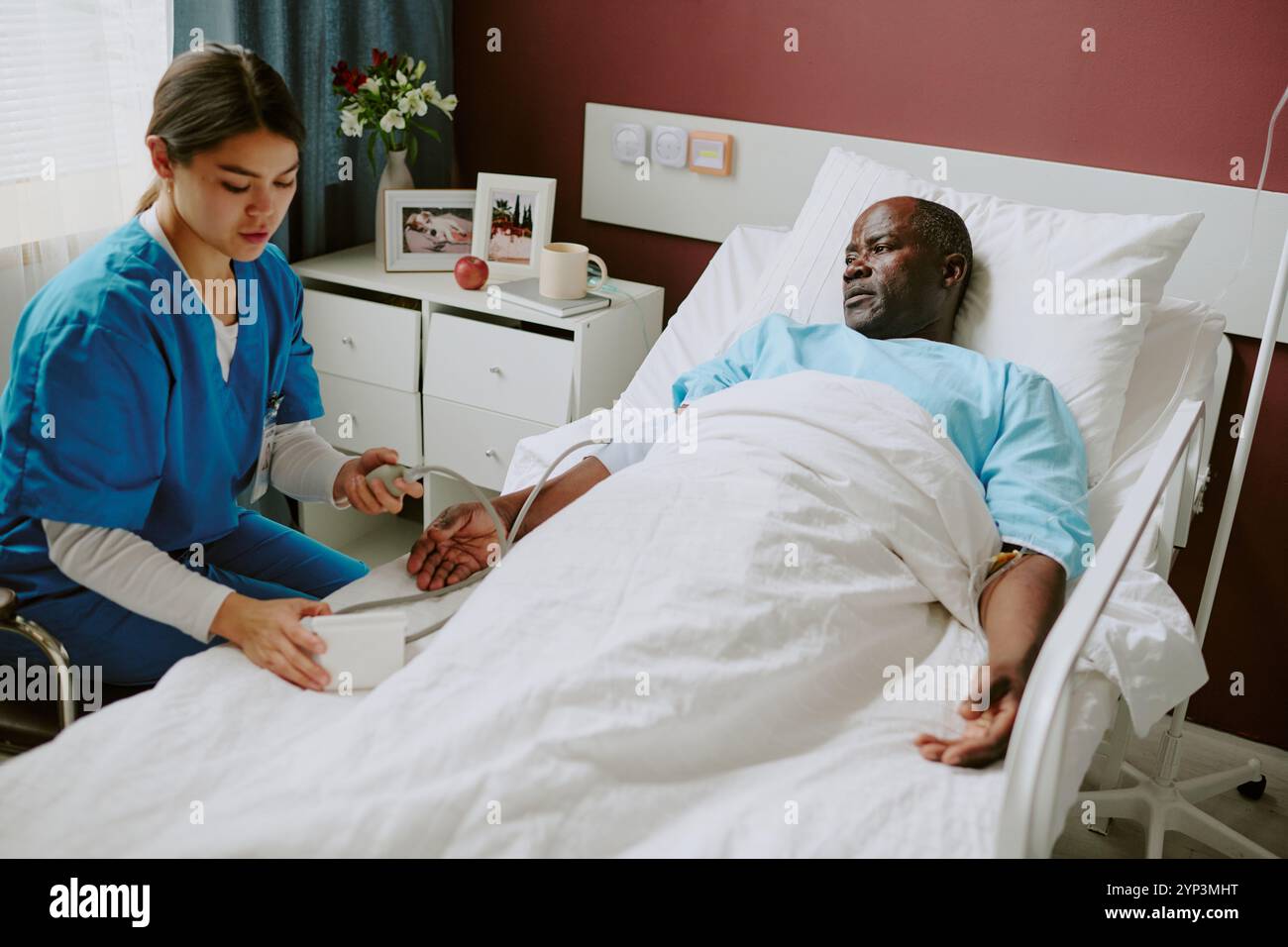 Nurse assisting an elderly patient in hospital bed during medical checkup, medical equipment ...