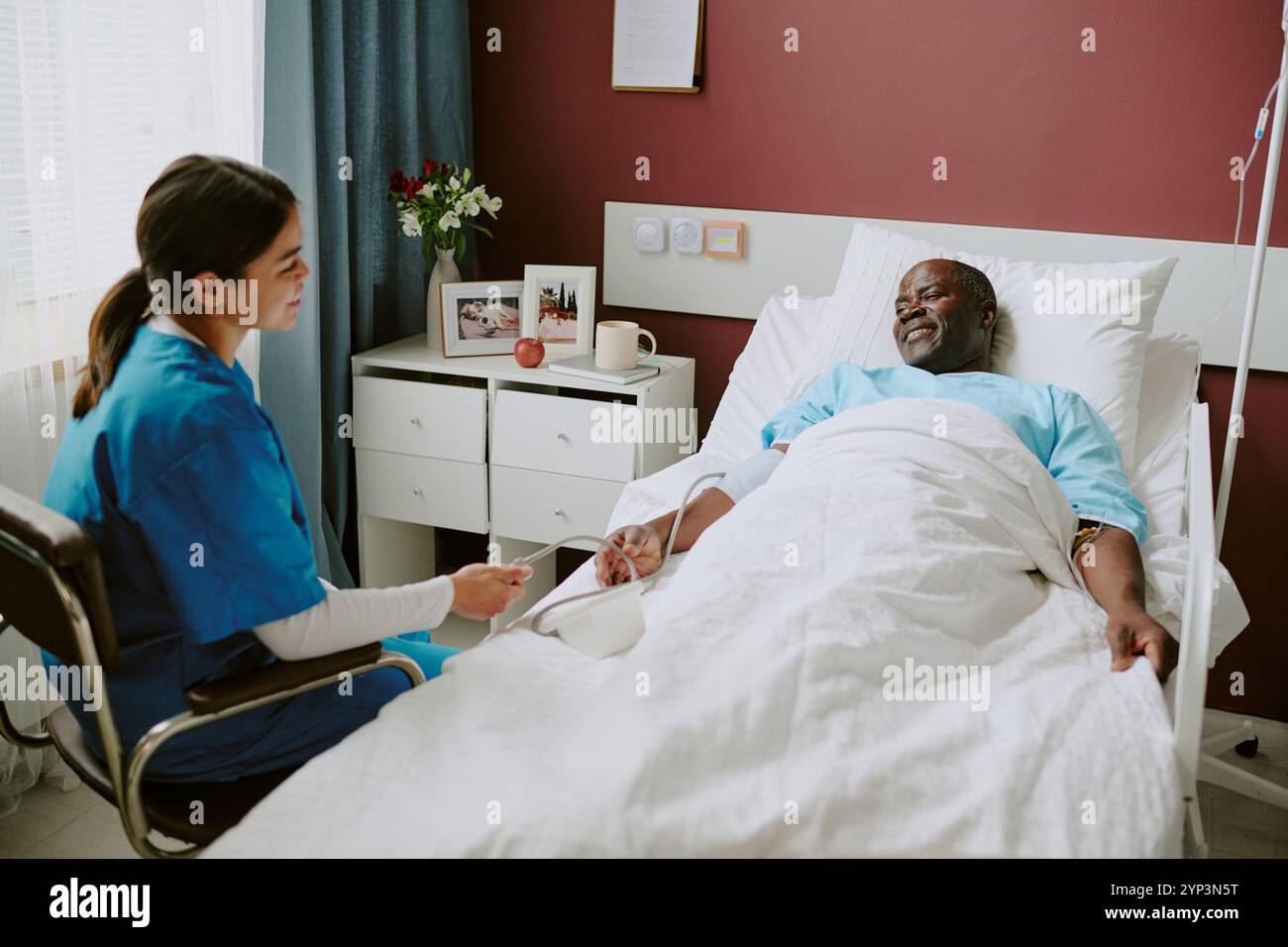 Nurse tending to bedridden patient in hospital room, providing care and ...