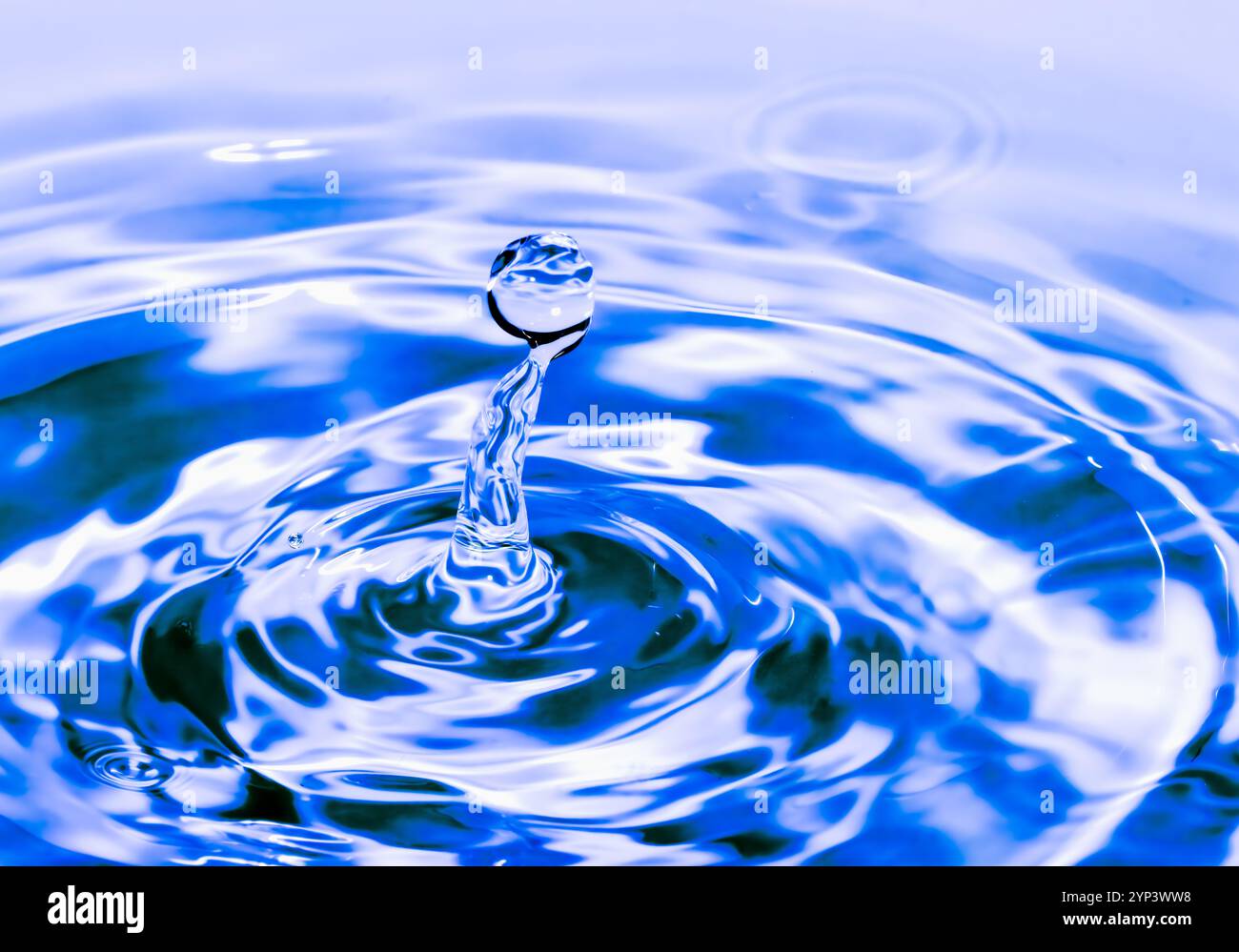A close-up of a water droplet splash. The droplet creates ripples and ...