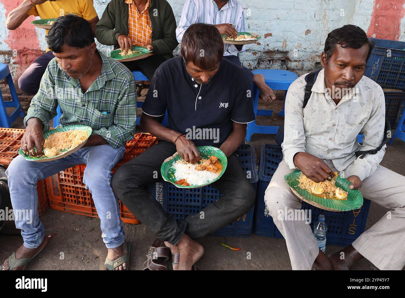 Men eating chicken biryani on disposable plates from a food stall in ...
