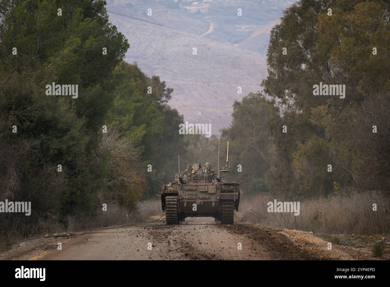 An Israeli army armoured vehicle drives along a road near the ...