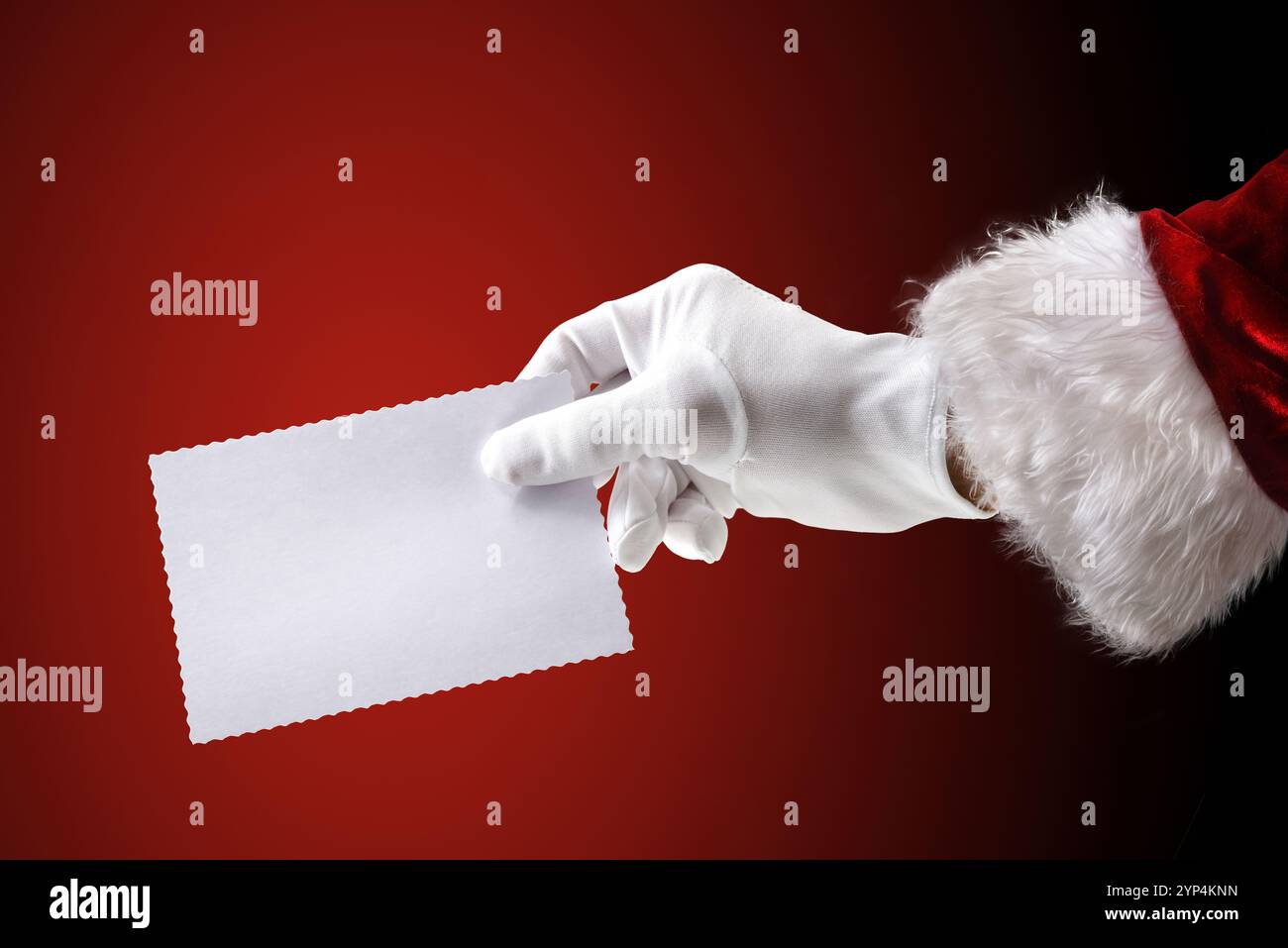 Santa Claus hand in suit and gloves holding blank paper card on red ...